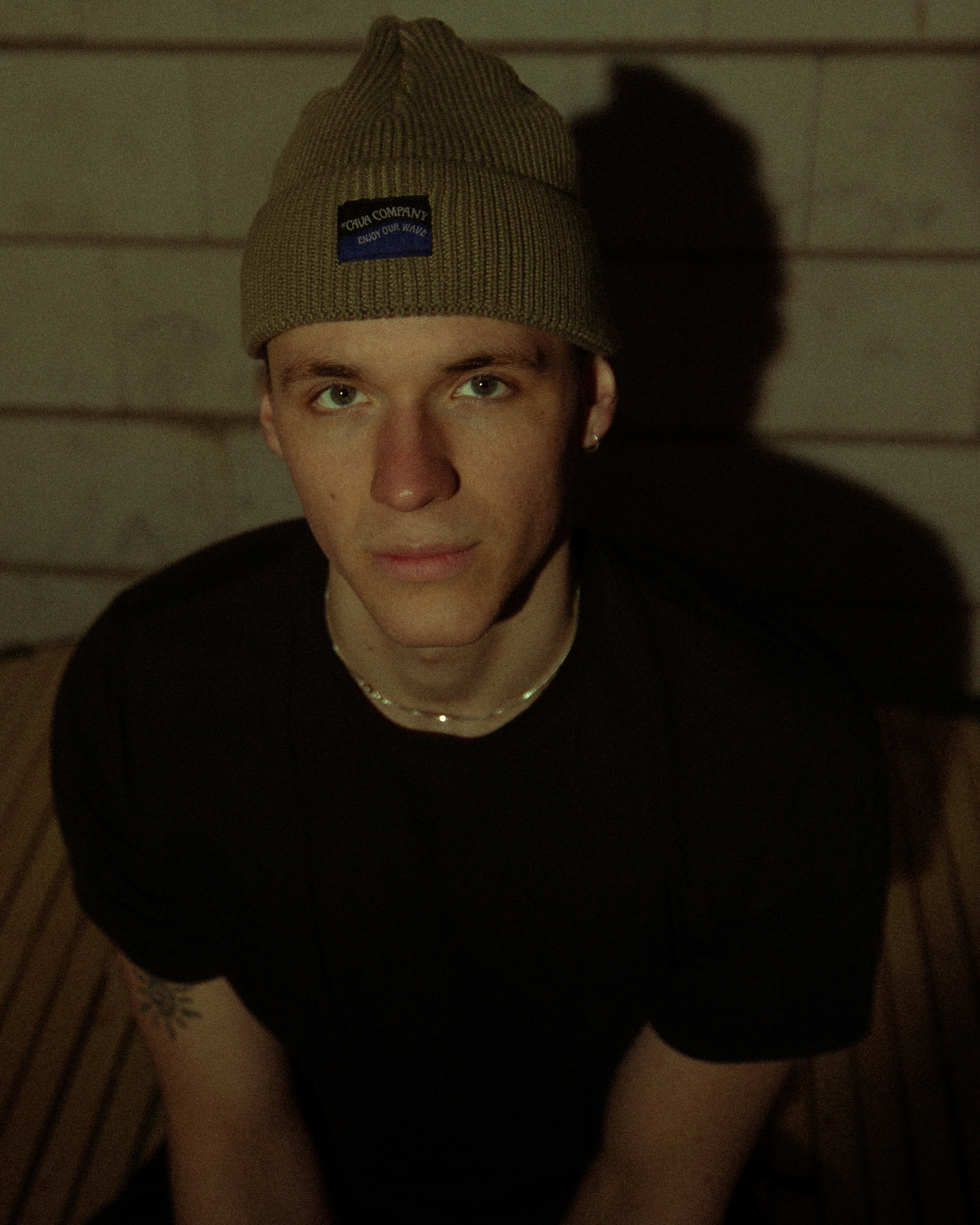 A young man wearing a beanie sitting on a bench photo – Free Portrait ...
