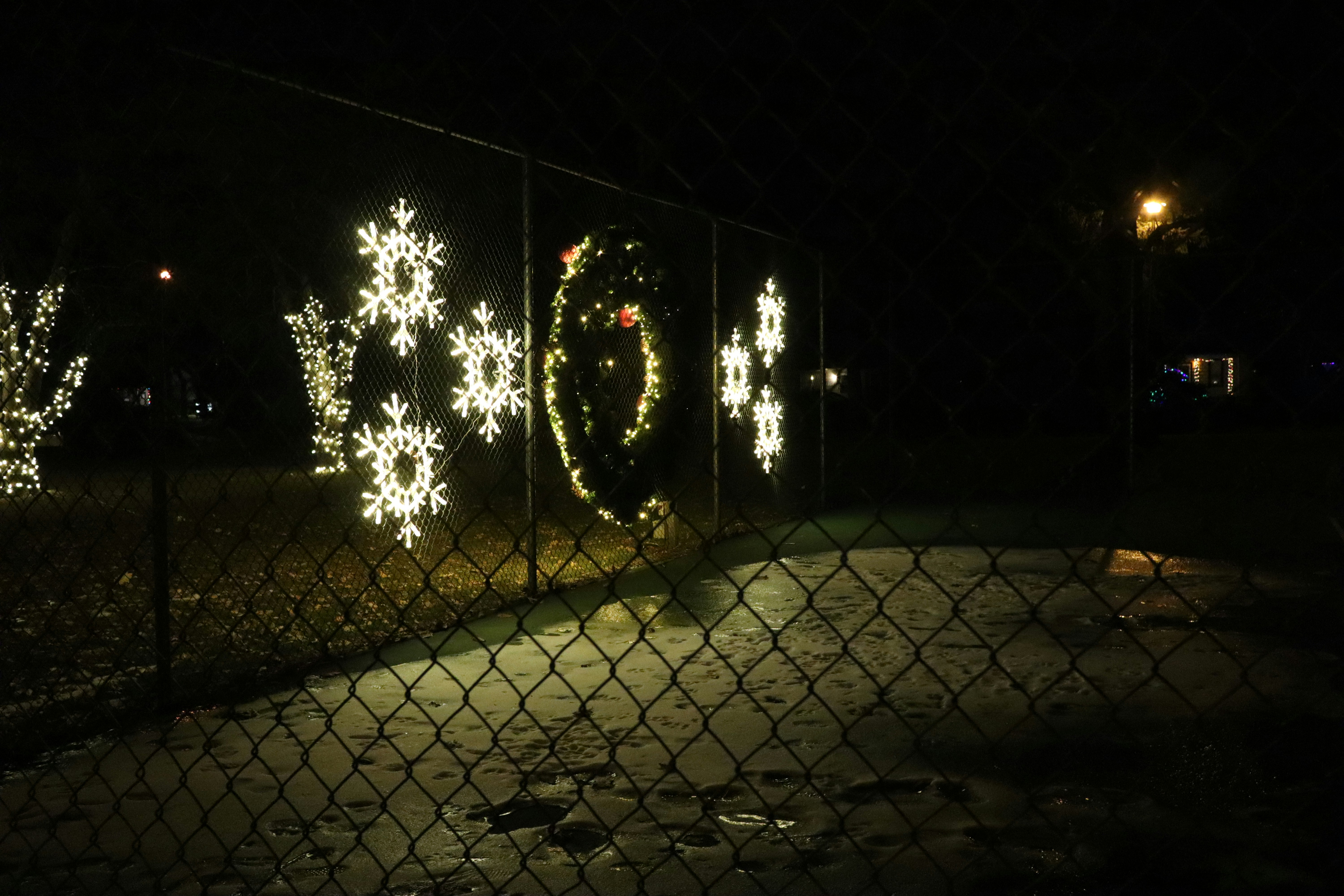 Snowflake Lanterns Along a Chain-Link Fence in Nighttime Winter Glow