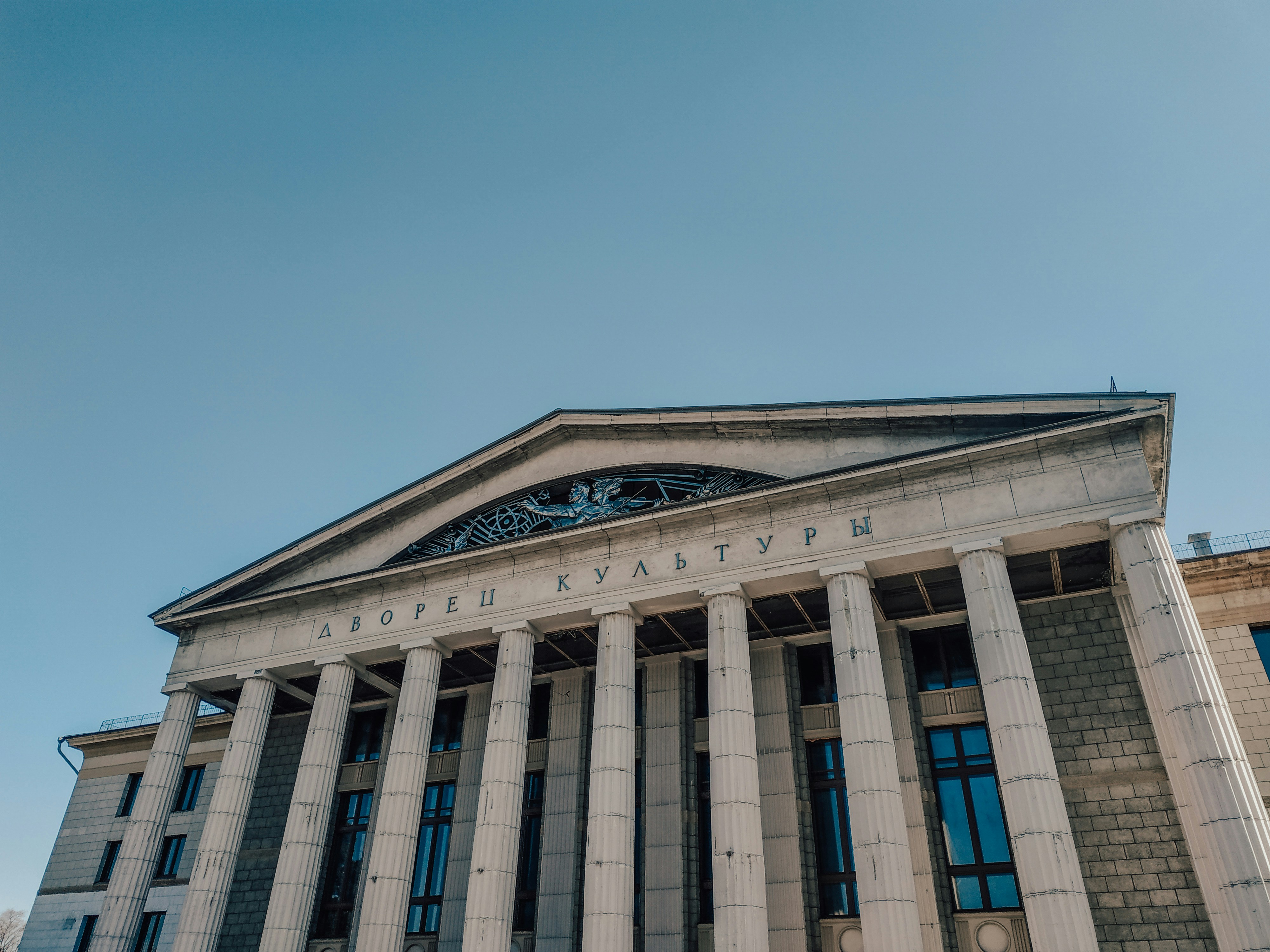 Neoclassical building facade with tall columns under a bright blue sky.