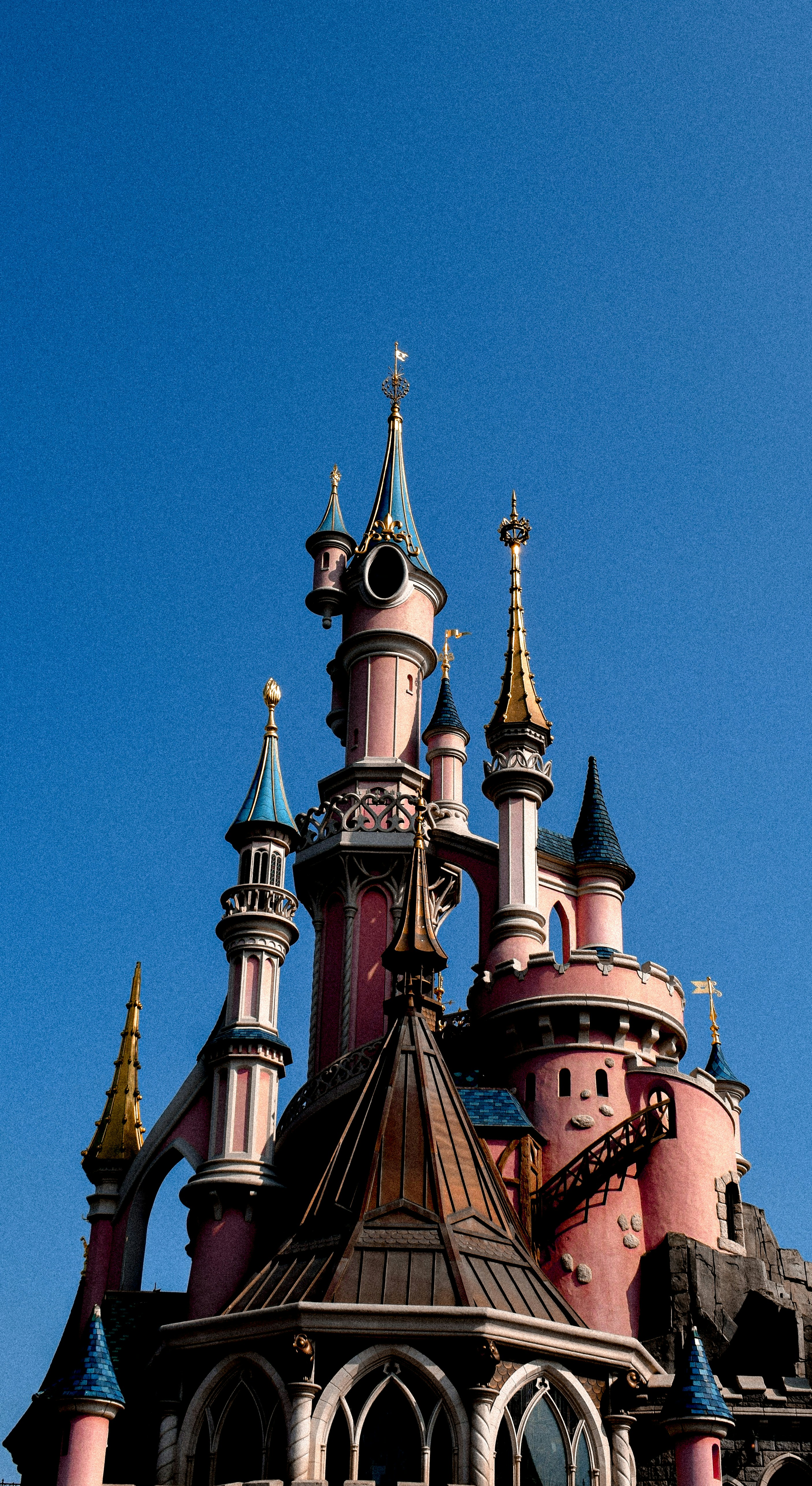 a pink and blue building with a clock on it's side