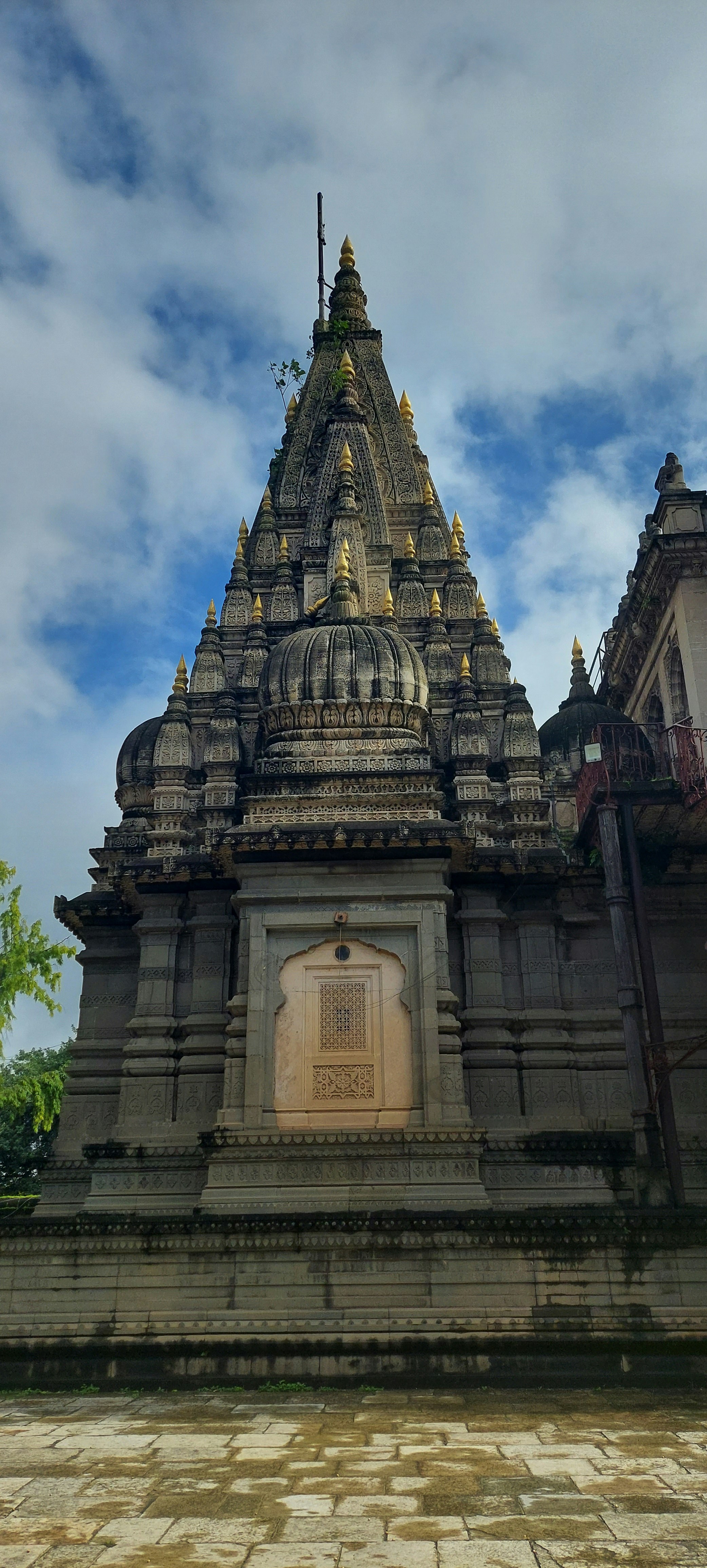 Intricate temple structure featuring ornate domes and golden spires against a cloudy sky.