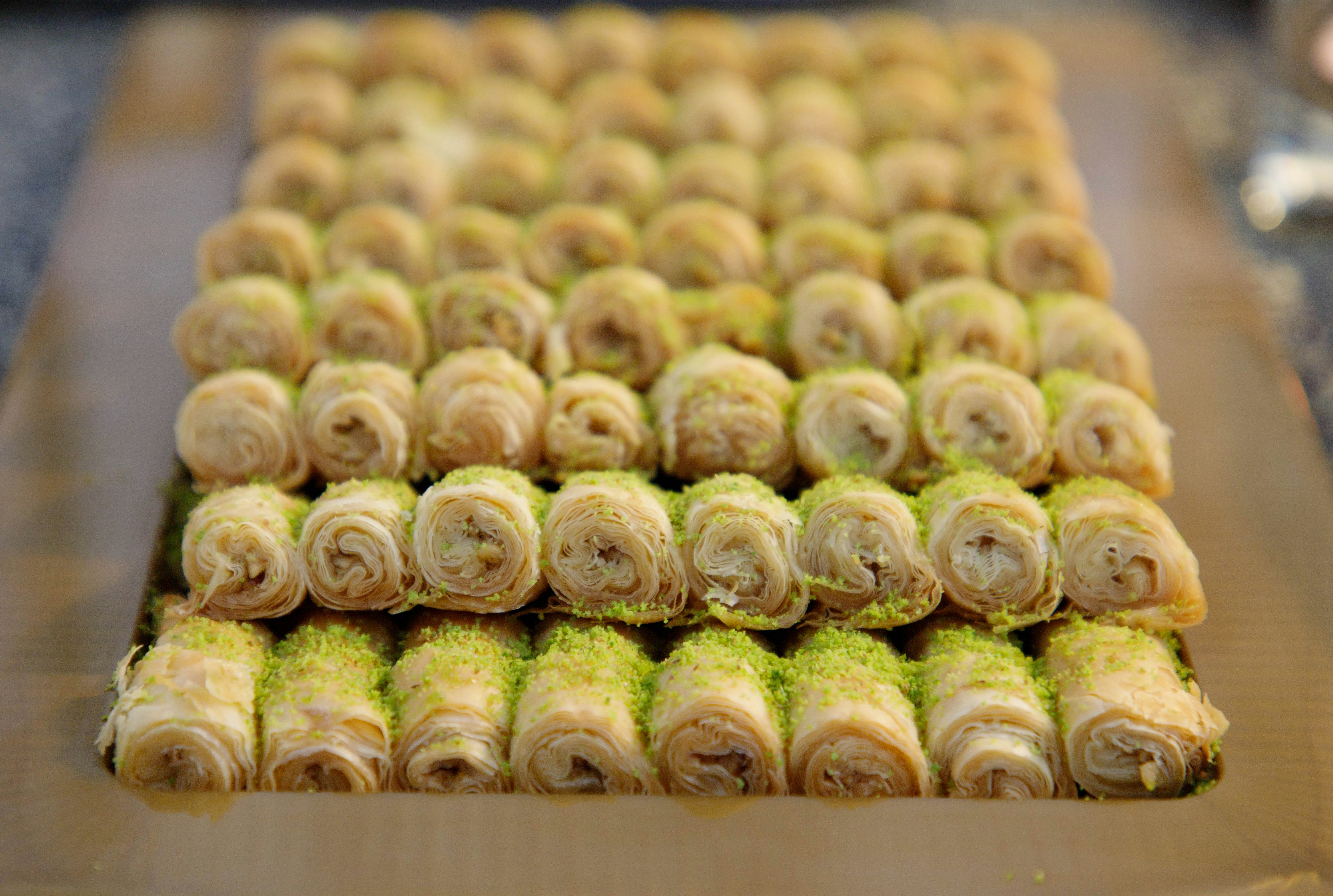 Rows of Pistachio-Topped Pastry Rolls on a Conveyor