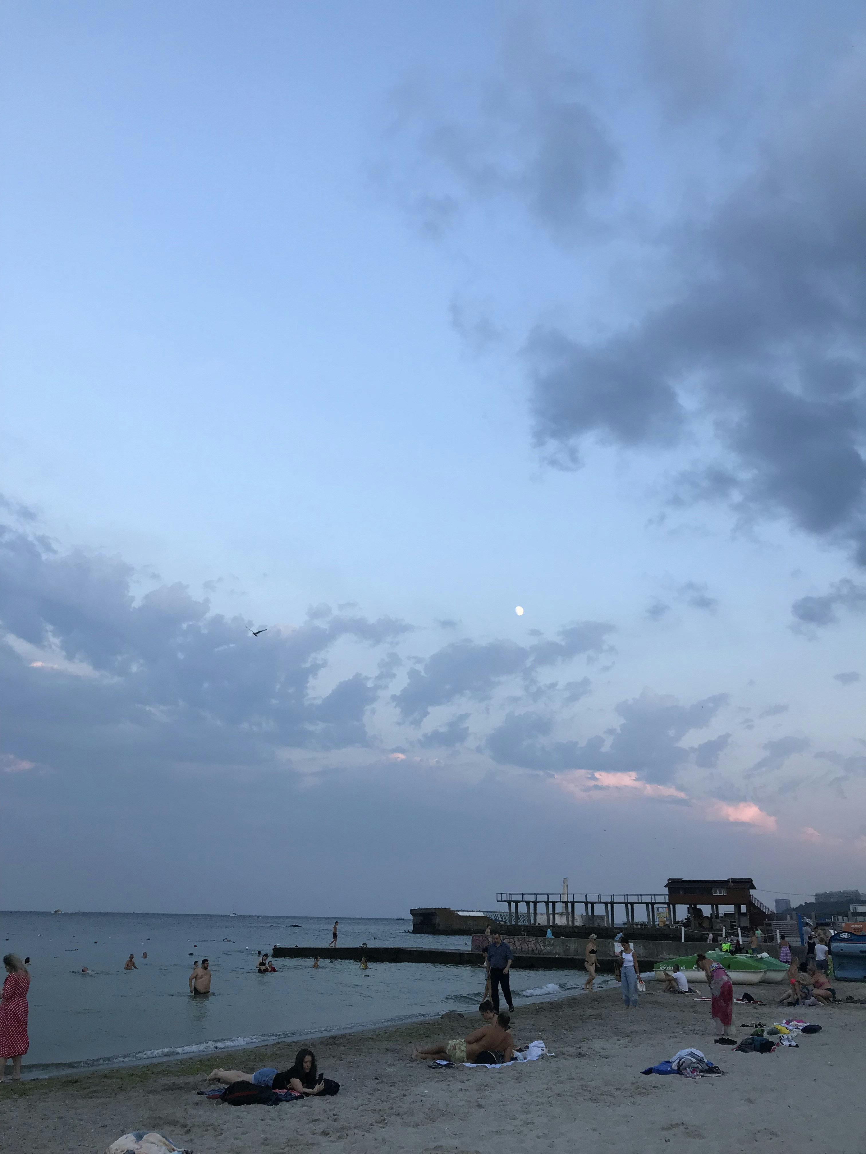 Moonlit Coastline: A Lively Beach at Dusk by the Pier