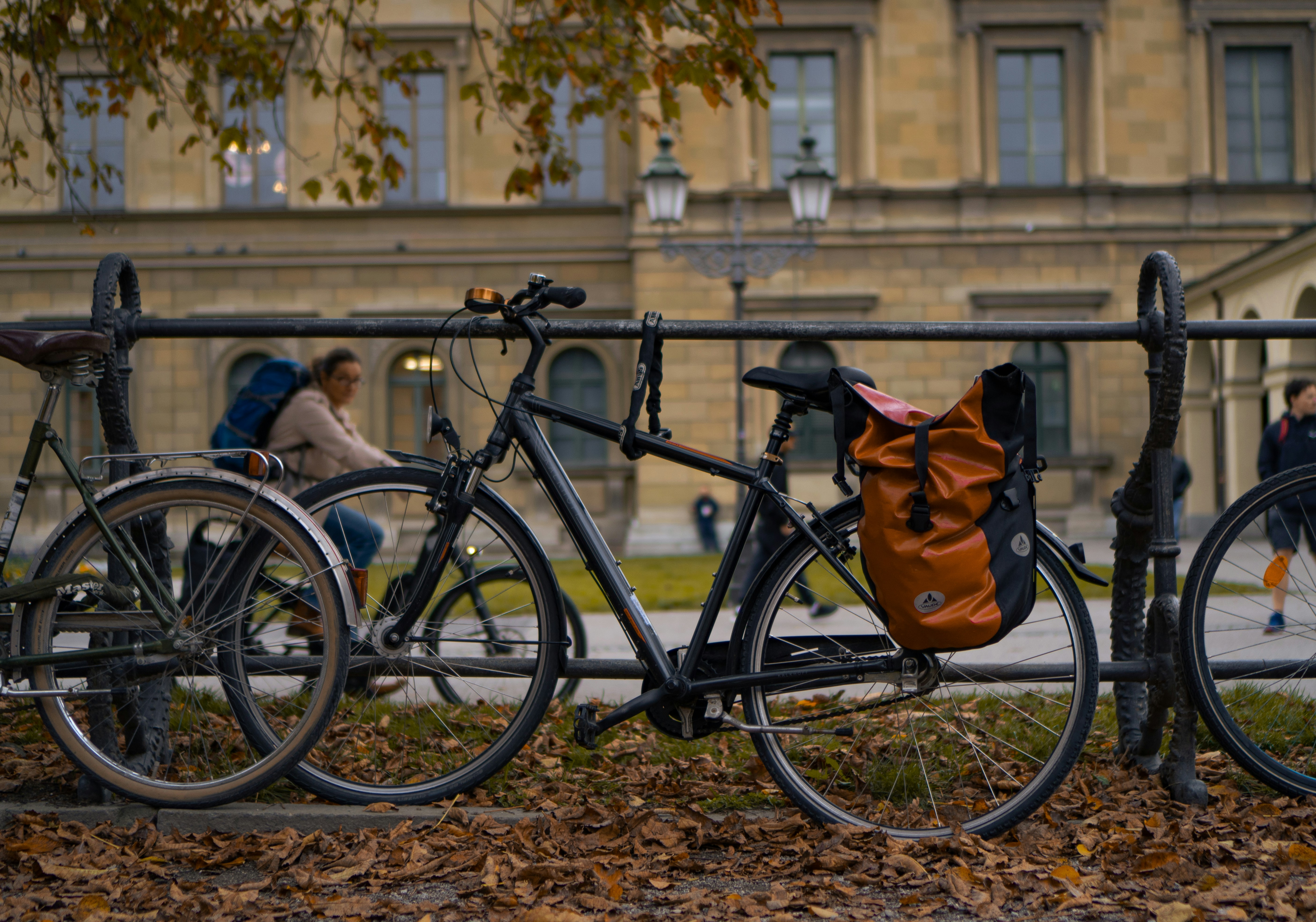 Two-city bikes tethered beside a stone facade and autumn leaves