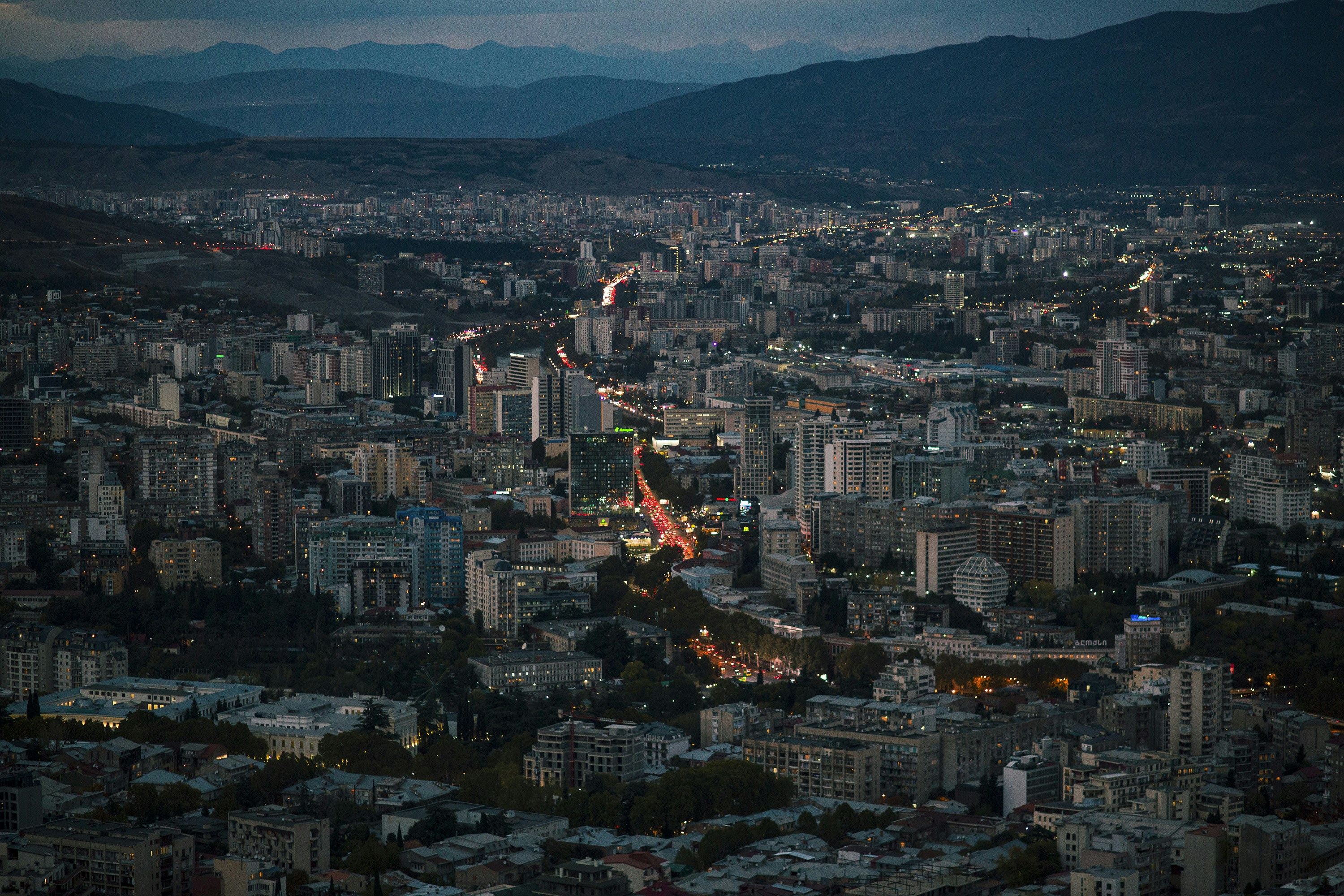 Neon Veins Through a Mountain-Guarded City at Dusk