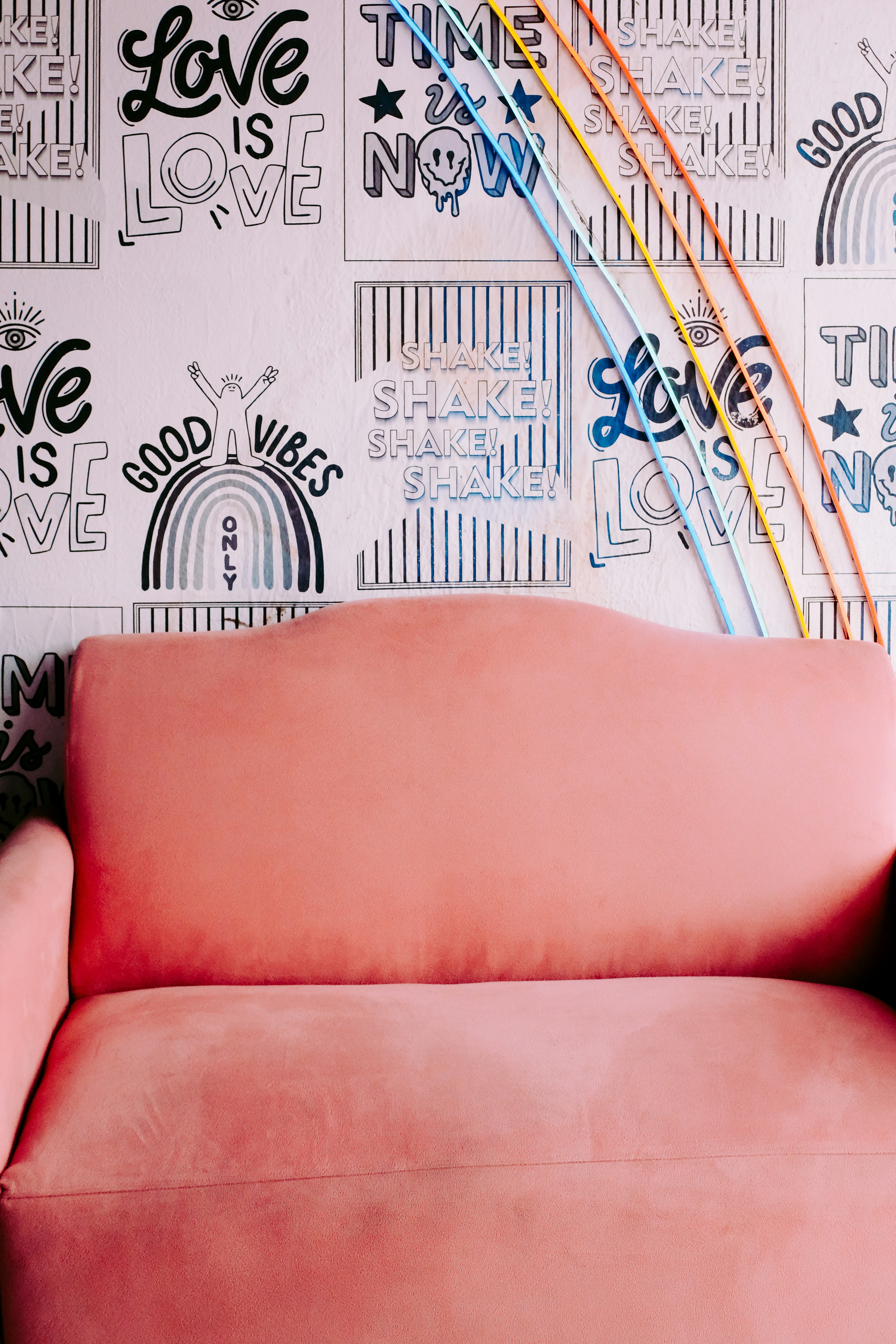 a pink couch sitting in front of a wall covered in wallpaper
