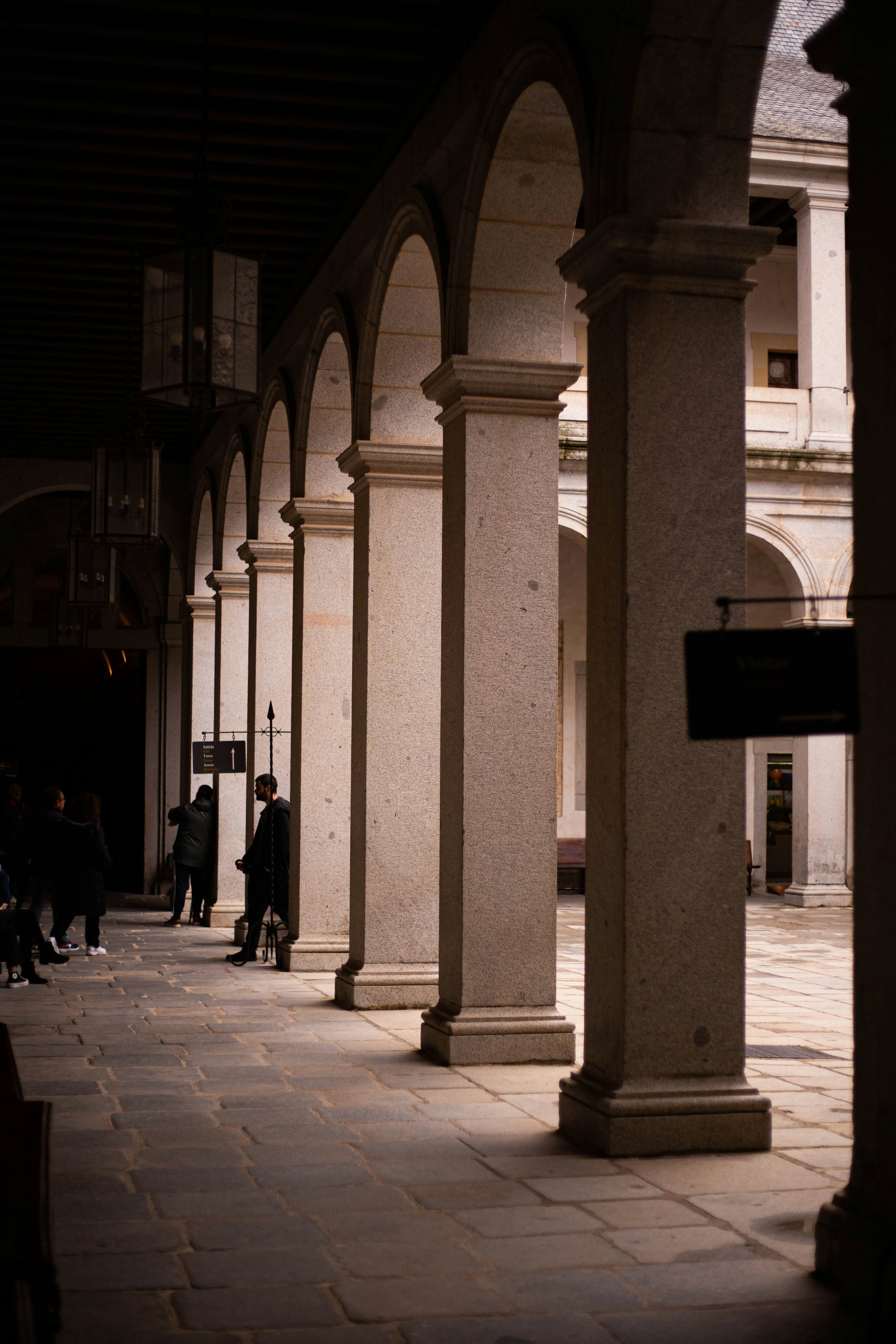 A group of people walking down a street next to tall pillars photo ...