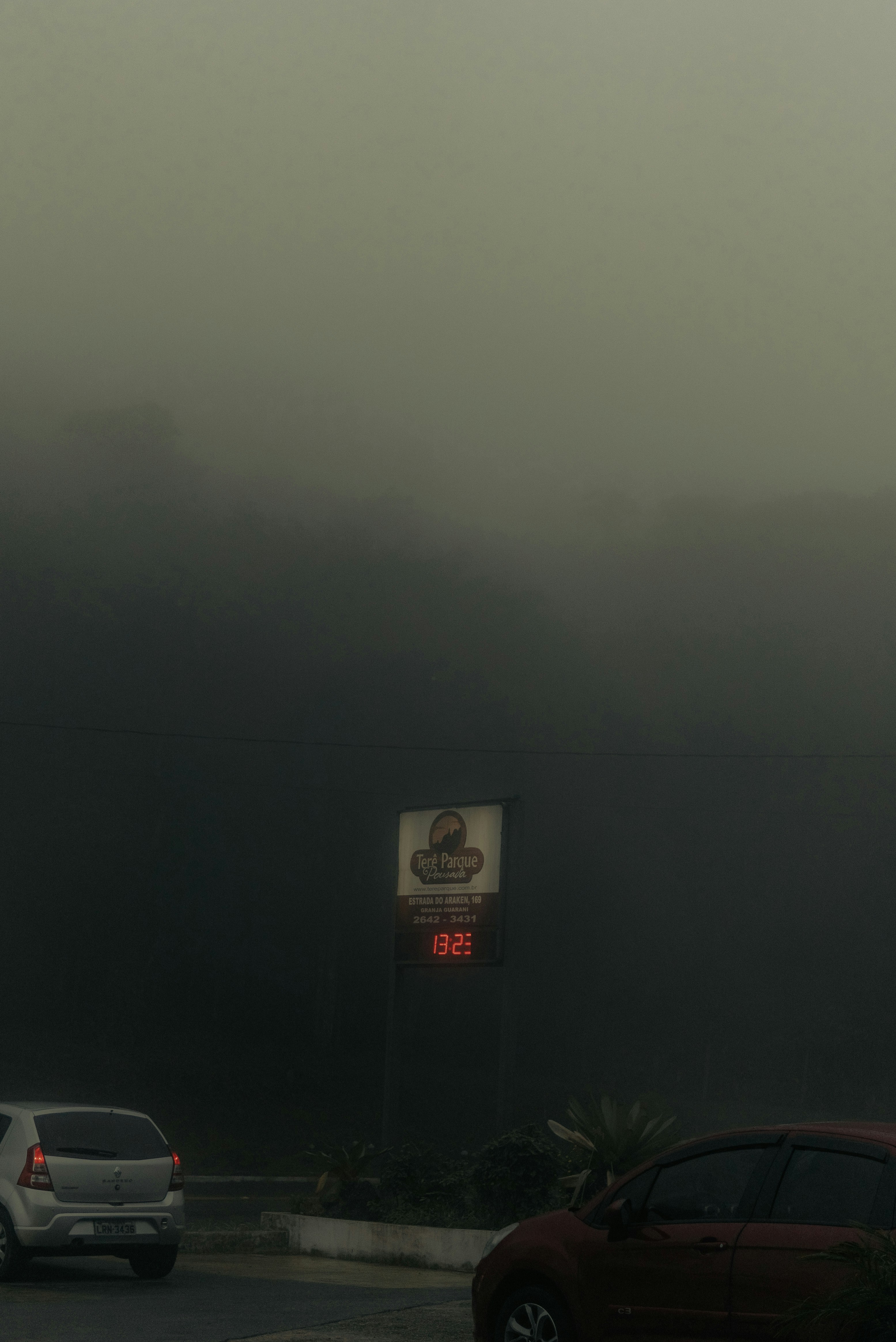 Red Clock Amid Fog: A Parking-Lot Sign Piercing the Haze