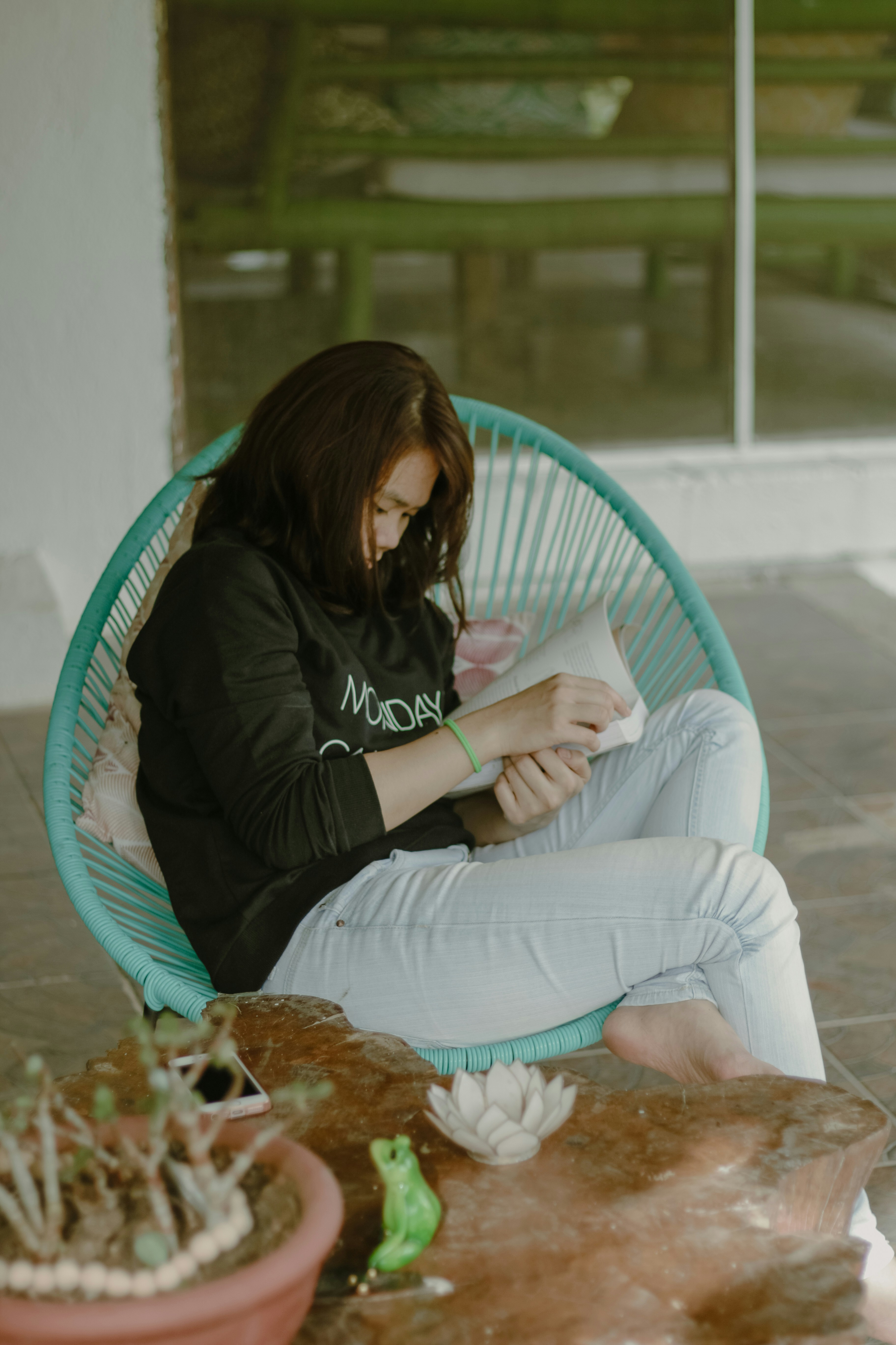 A woman sitting in a chair reading a book photo – Free Reading book ...