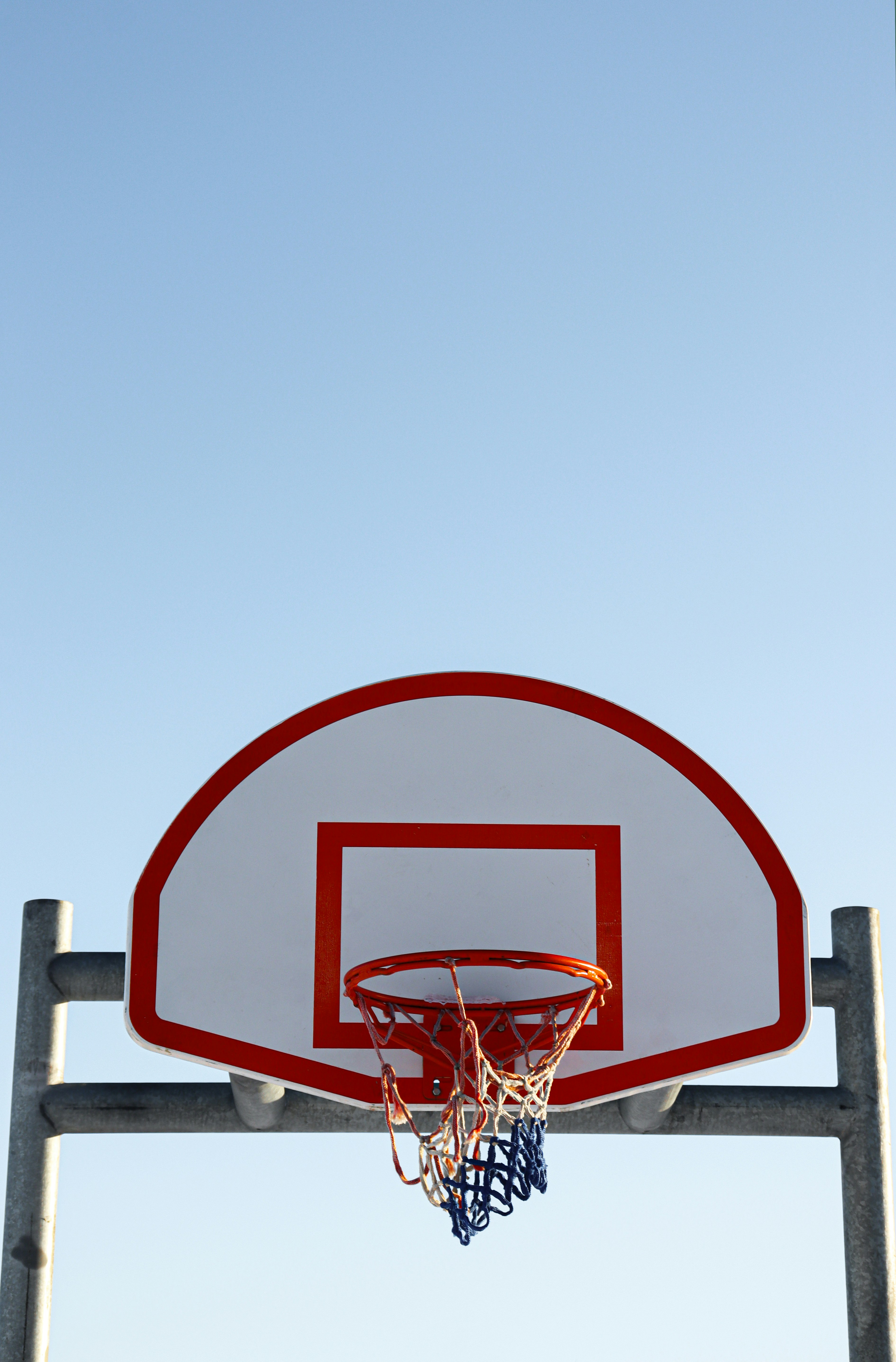 A red and white basketball hoop with a blue sky in the background photo ...