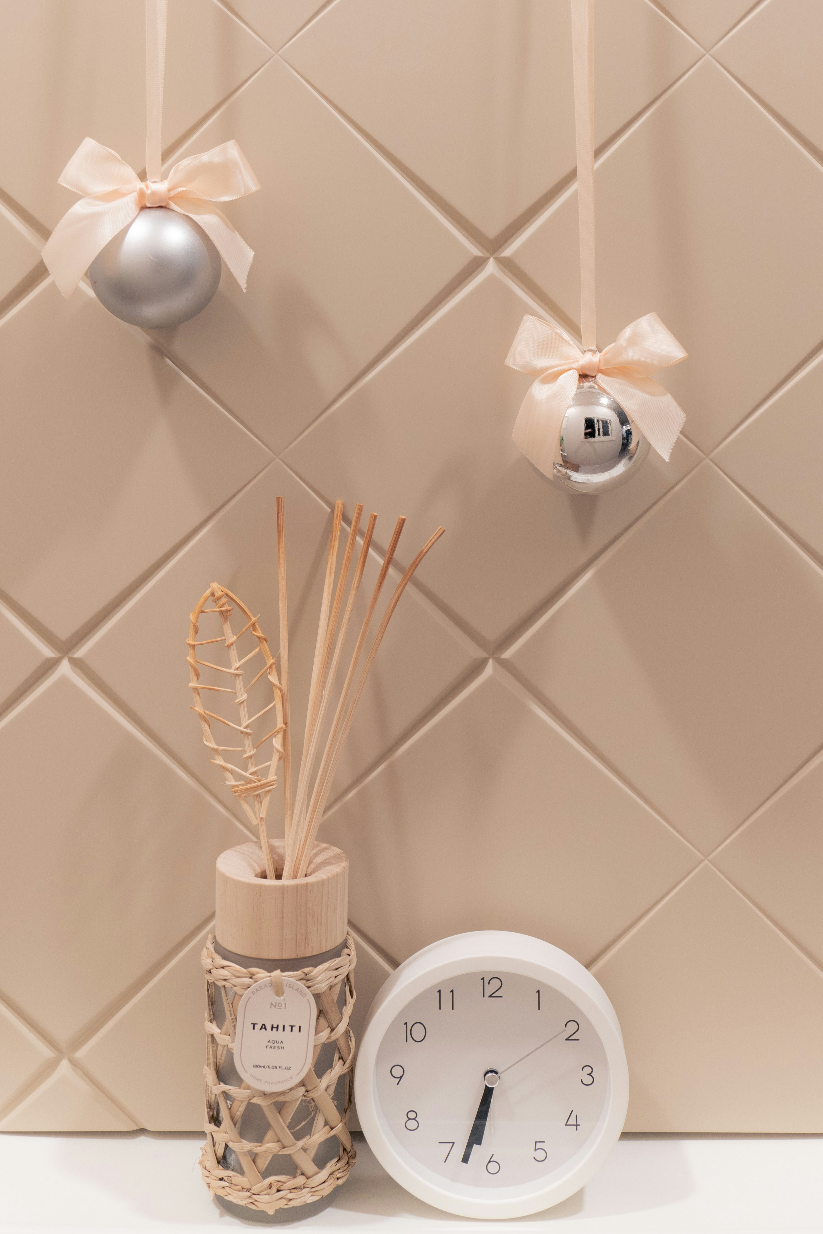 Beige Quiet: A Minimalist Diffuser Still Life with Ribboned Ornaments and Clock