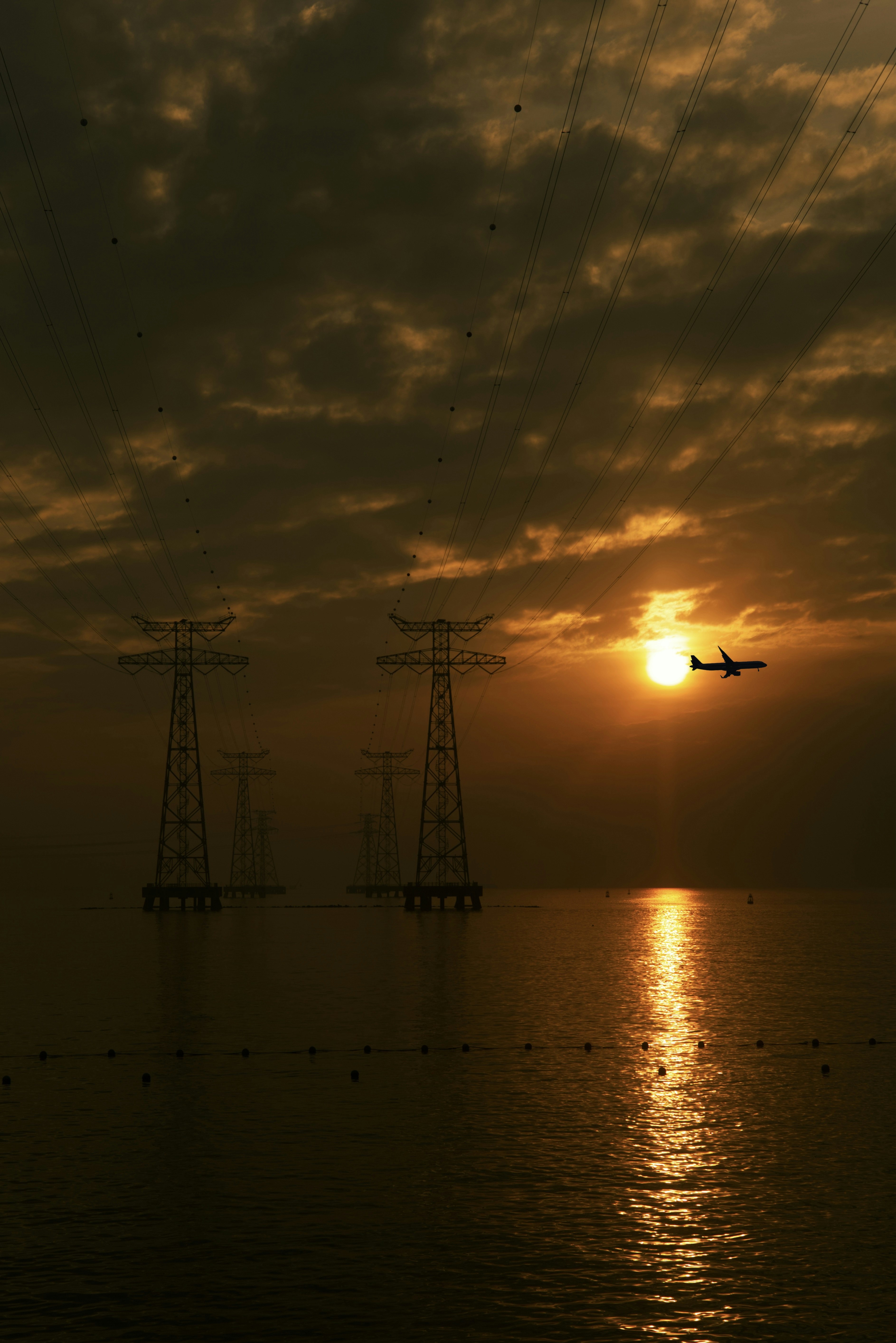 Sunset Descent: A Plane Crossing the Fiery Horizon Over Tidal Towers