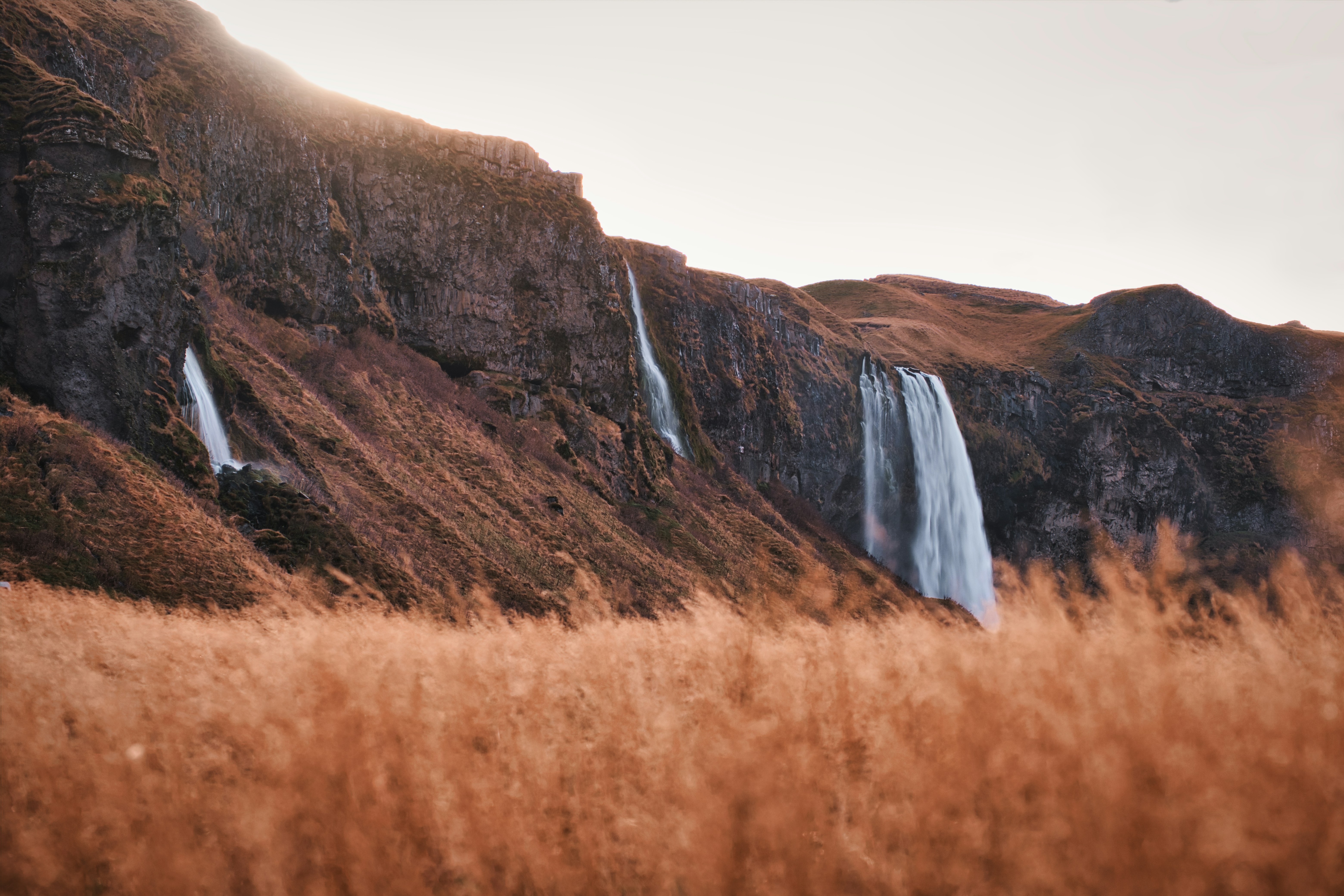 Amber Cascade on a Cliff: Waterfall Framed by Golden Plains