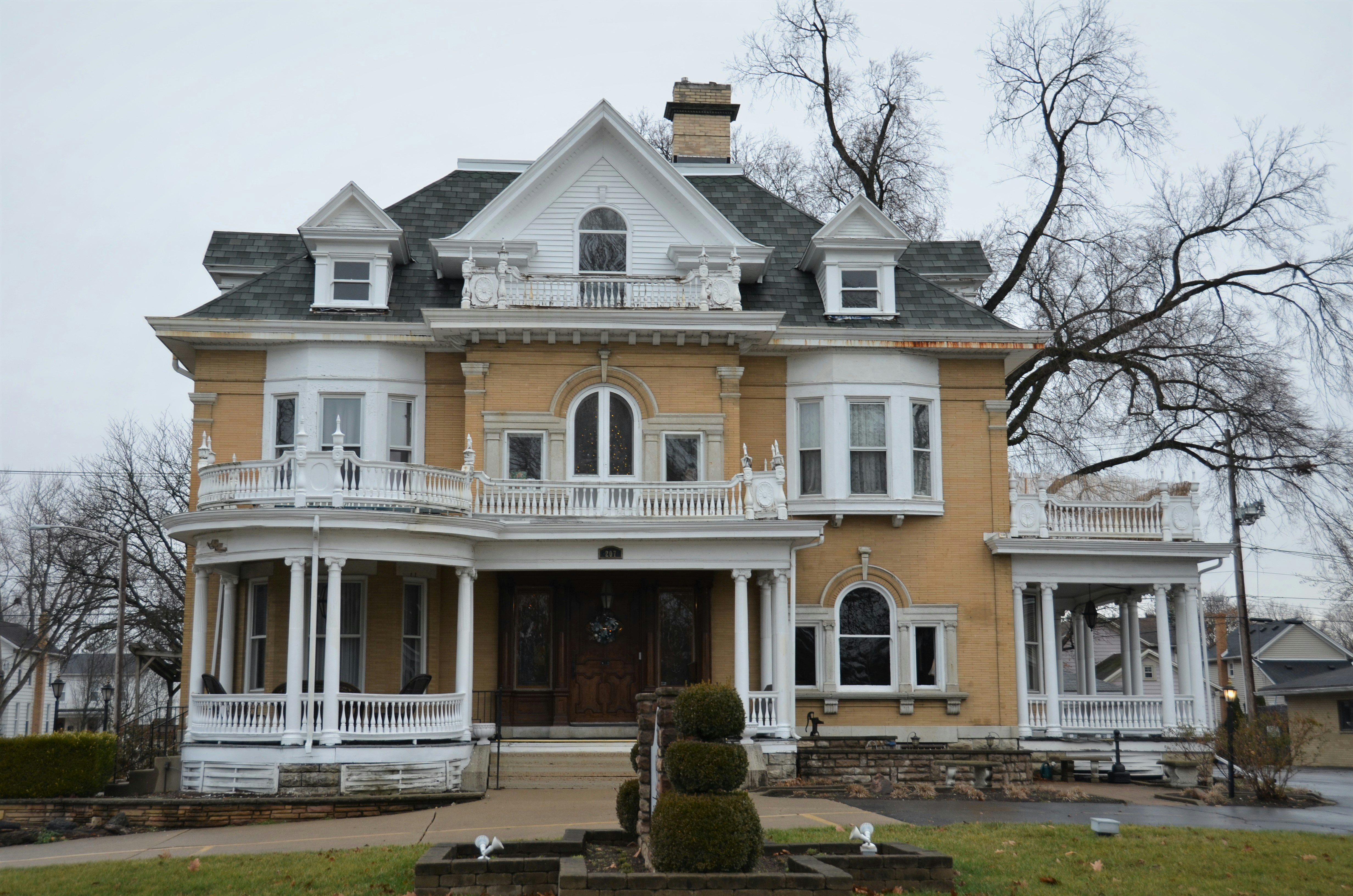 A large yellow house with white trim and windows photo – Free Housing ...