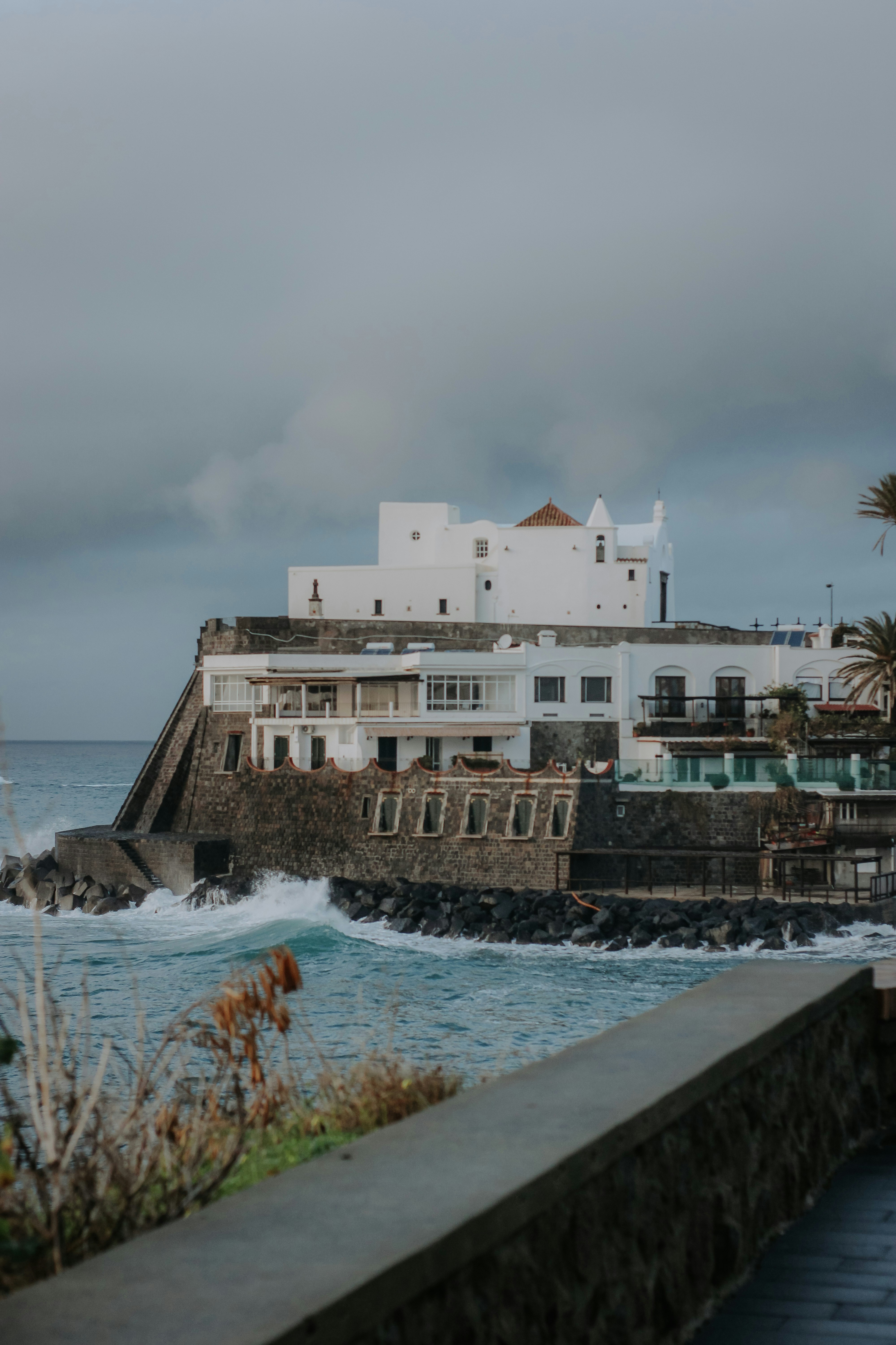 A large white building sitting on top of a cliff next to the ocean ...