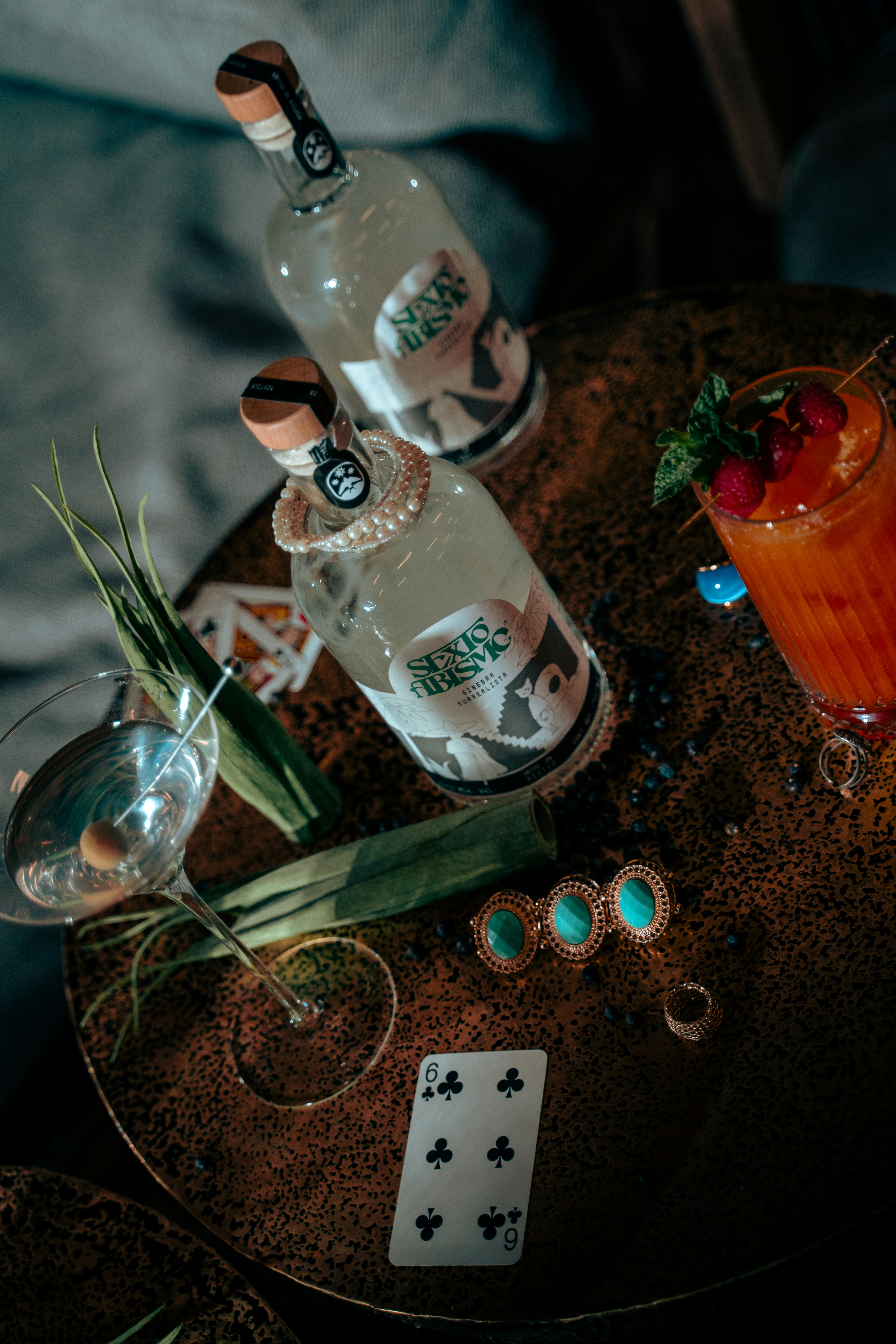 A table topped with a bottle of booze next to a glass of orange juice ...