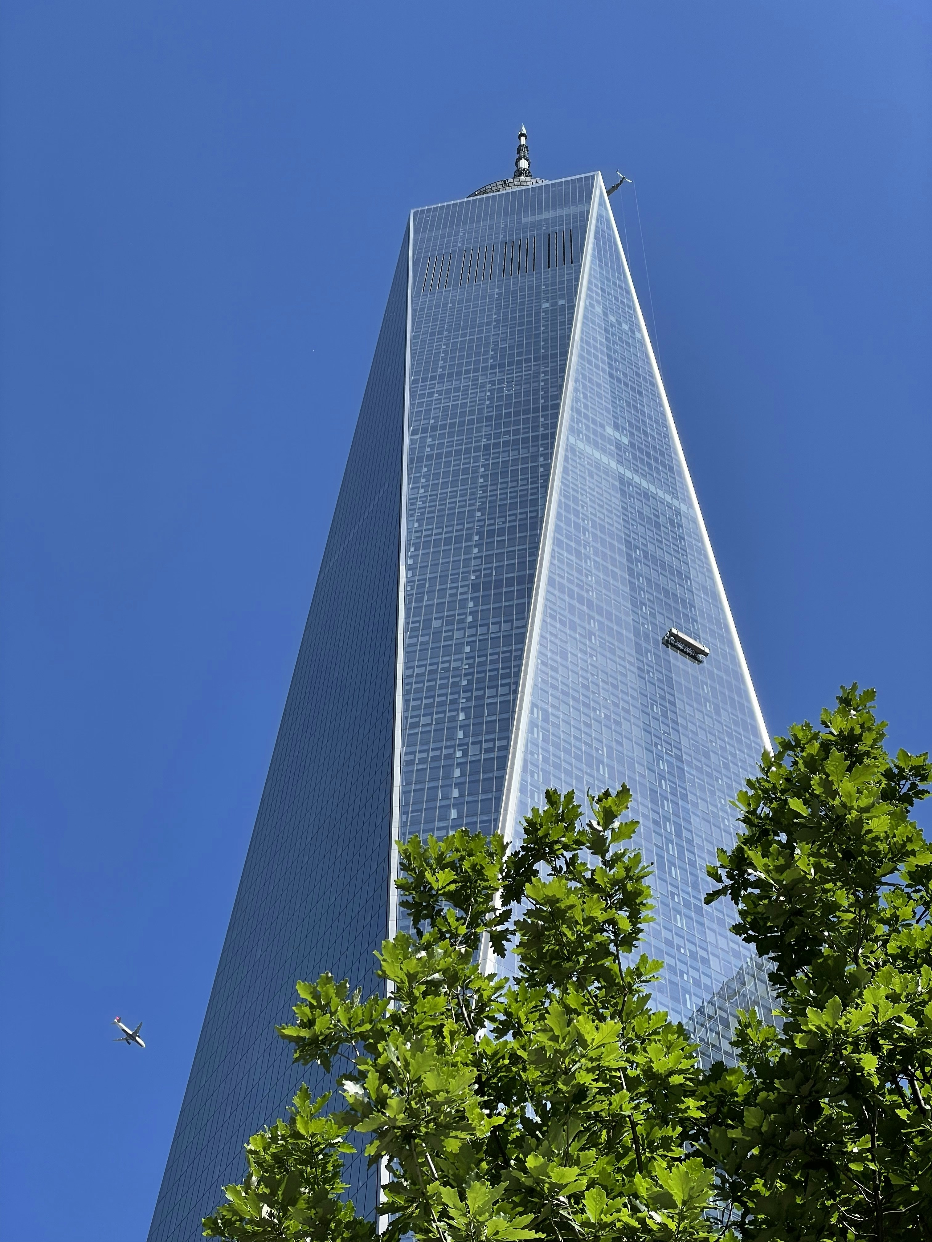 A very tall building with a plane flying in the sky photo – Free World ...