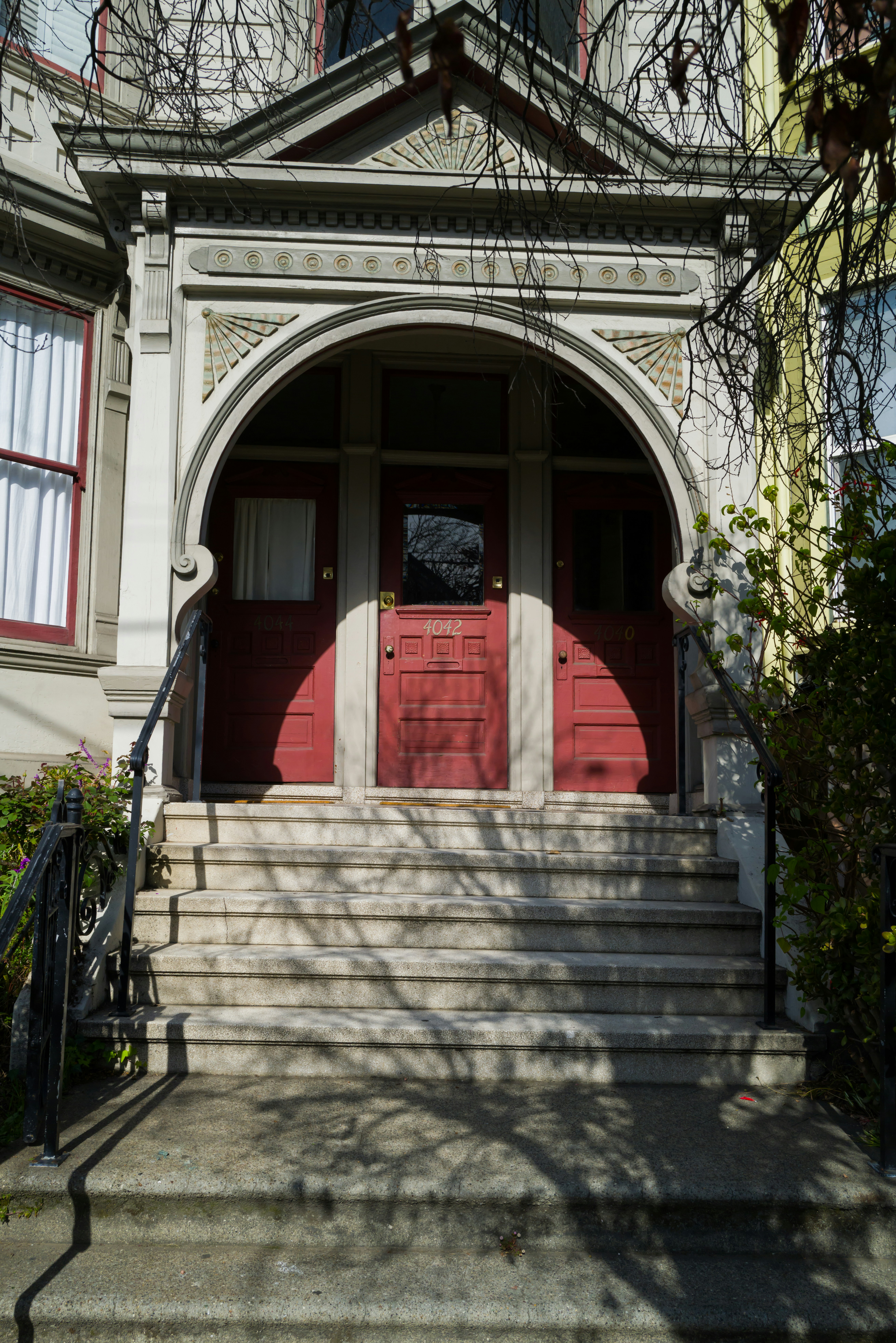 Red Archway Entrance: Sunlit Steps to a Quiet Victorian Doorway