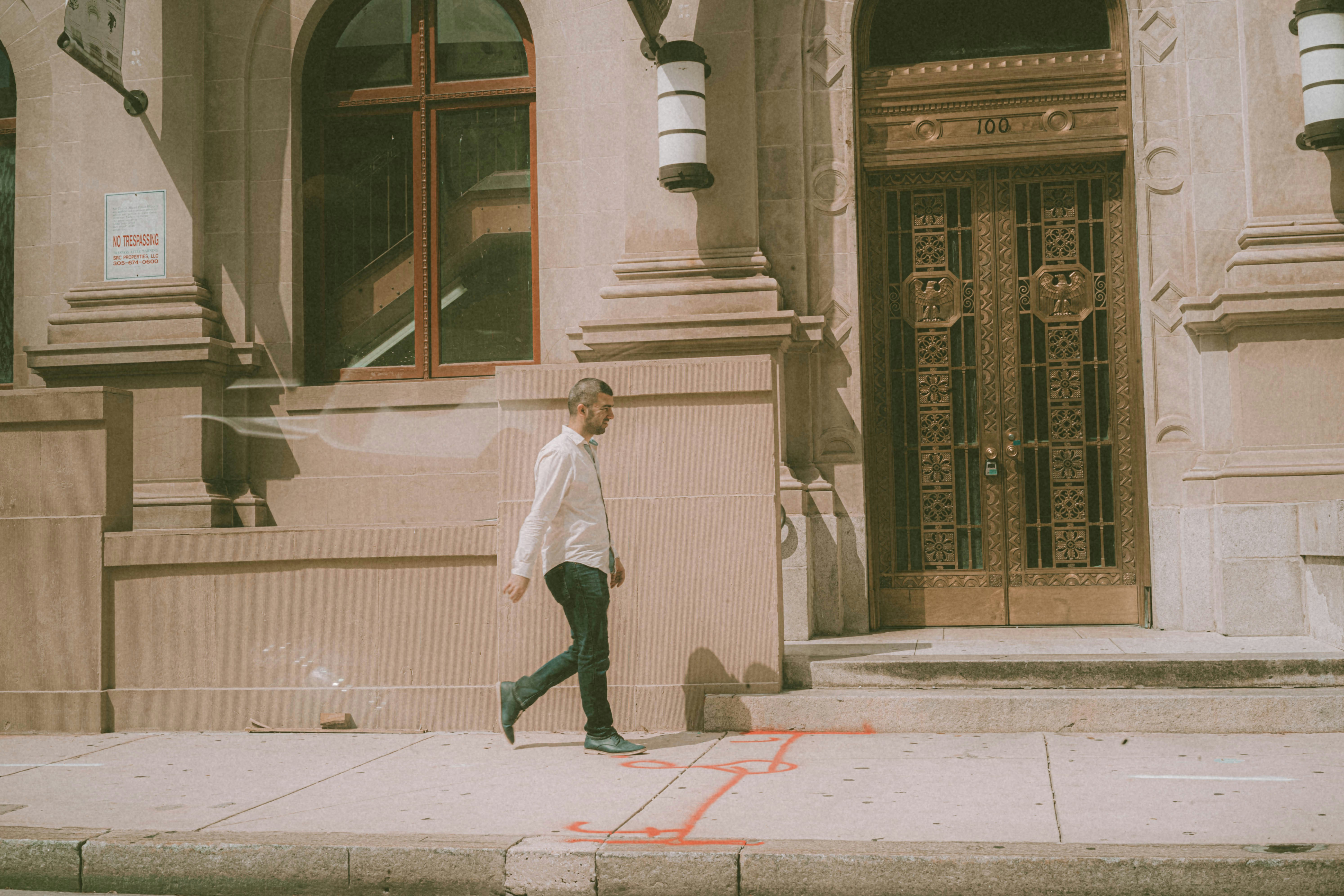 A man walking down a street next to a tall building photo – Free Adult ...