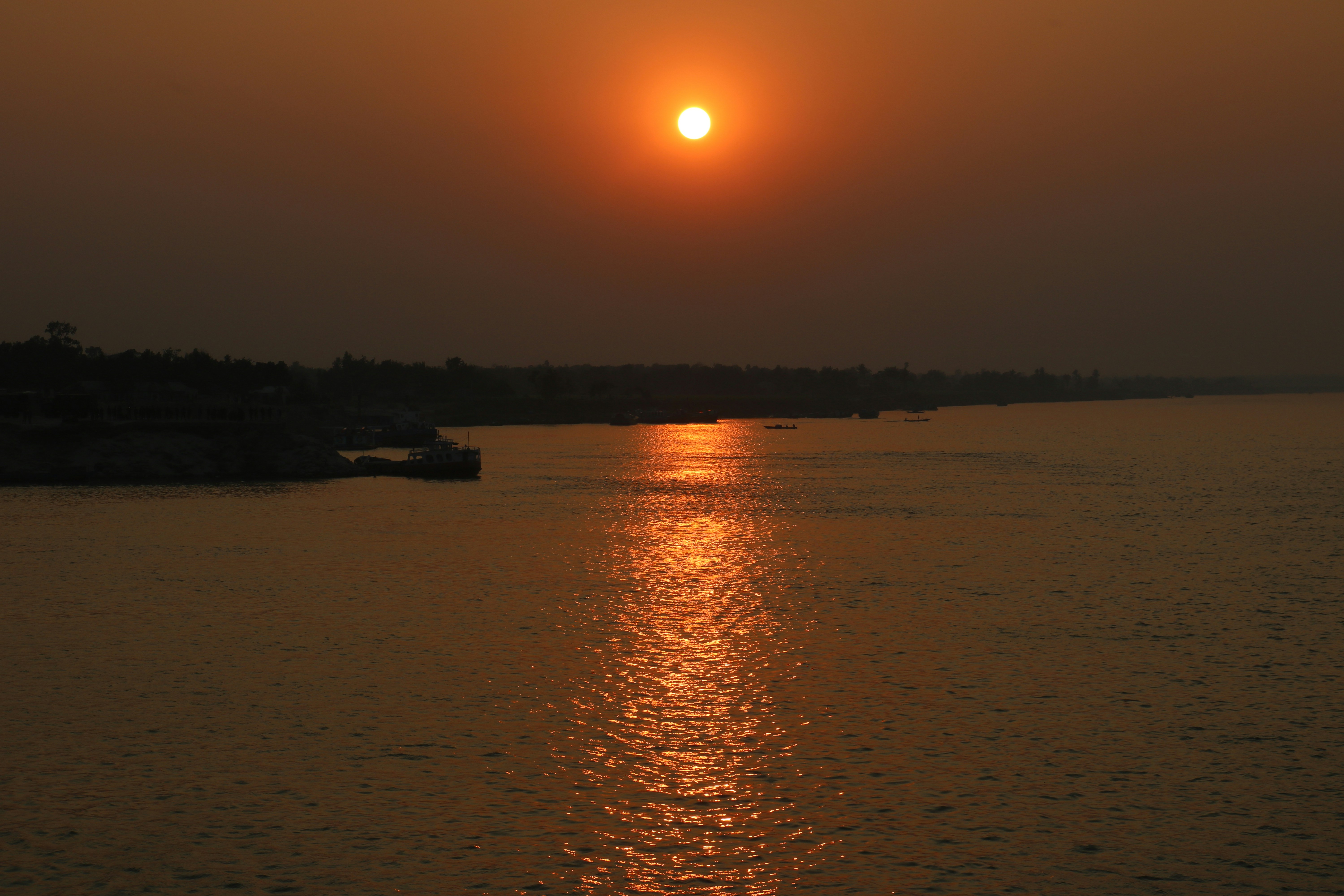 The sun is setting over a body of water photo – Free Padma river Image ...