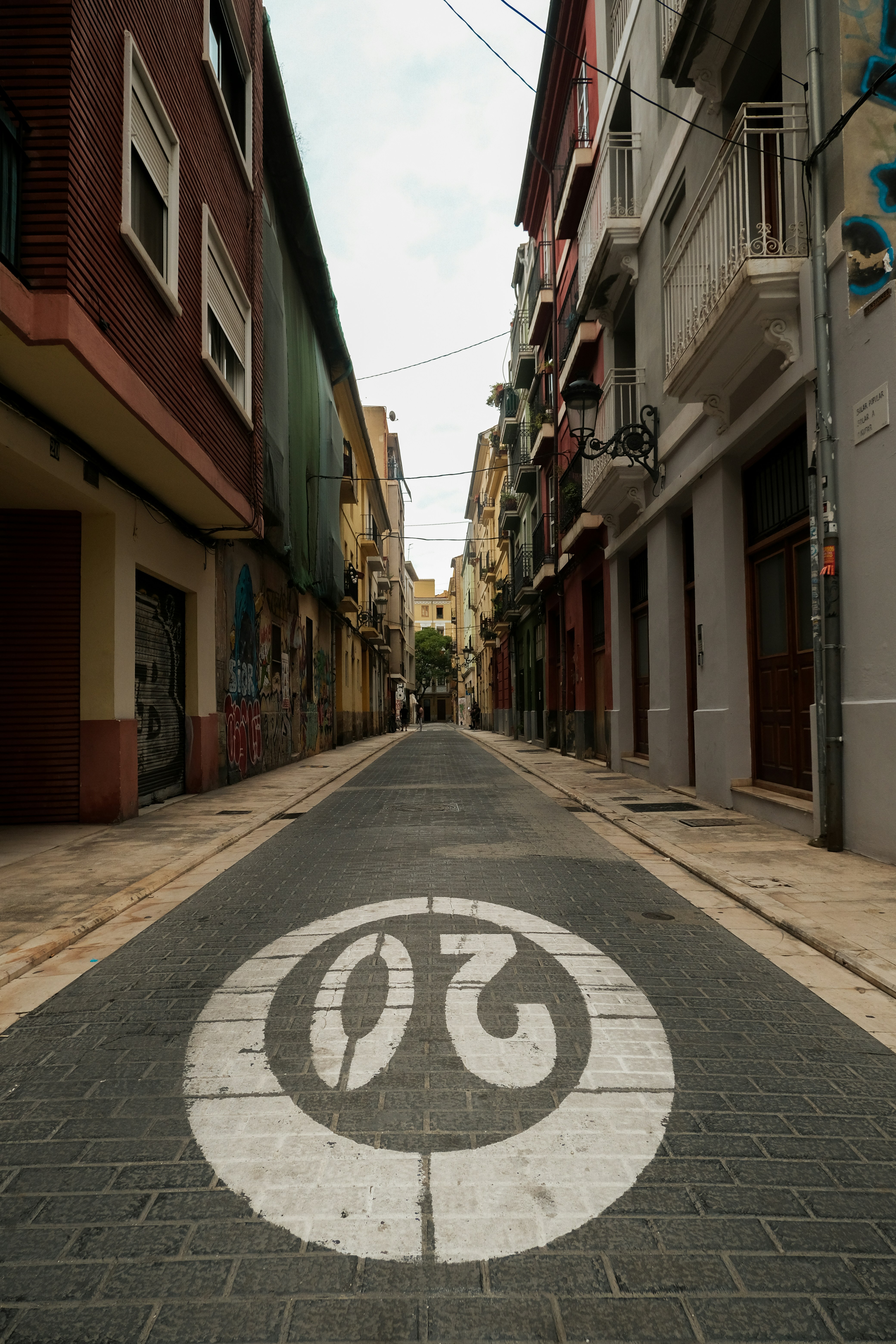 Circular 20 on a sunlit urban street guides the eye toward a vanishing horizon