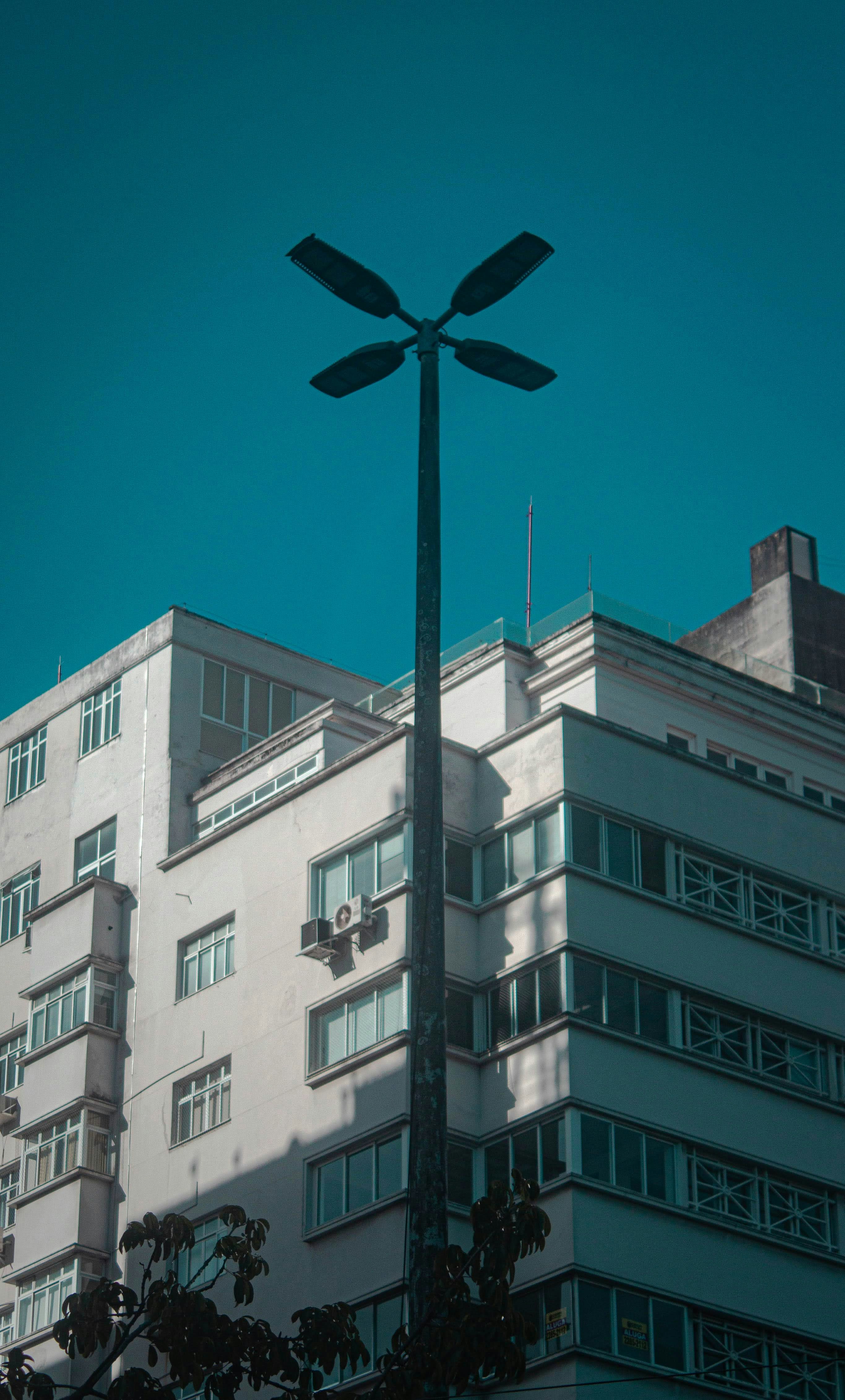 Teal Sky, Four-armed Streetlamp Over a Quiet Urban Facade