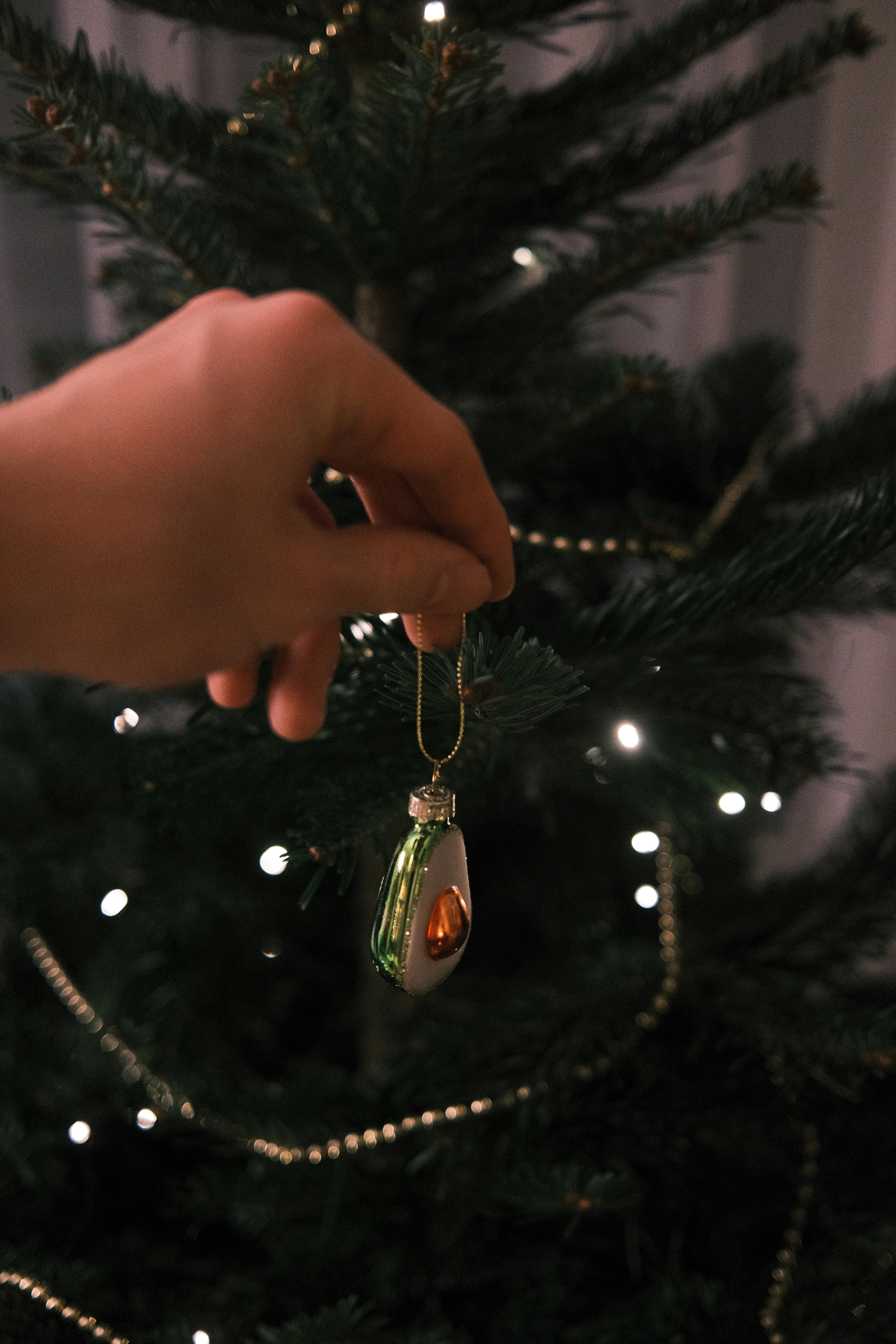 Teardrop Ornament Grasped Against a Fairy-Lit Christmas Tree