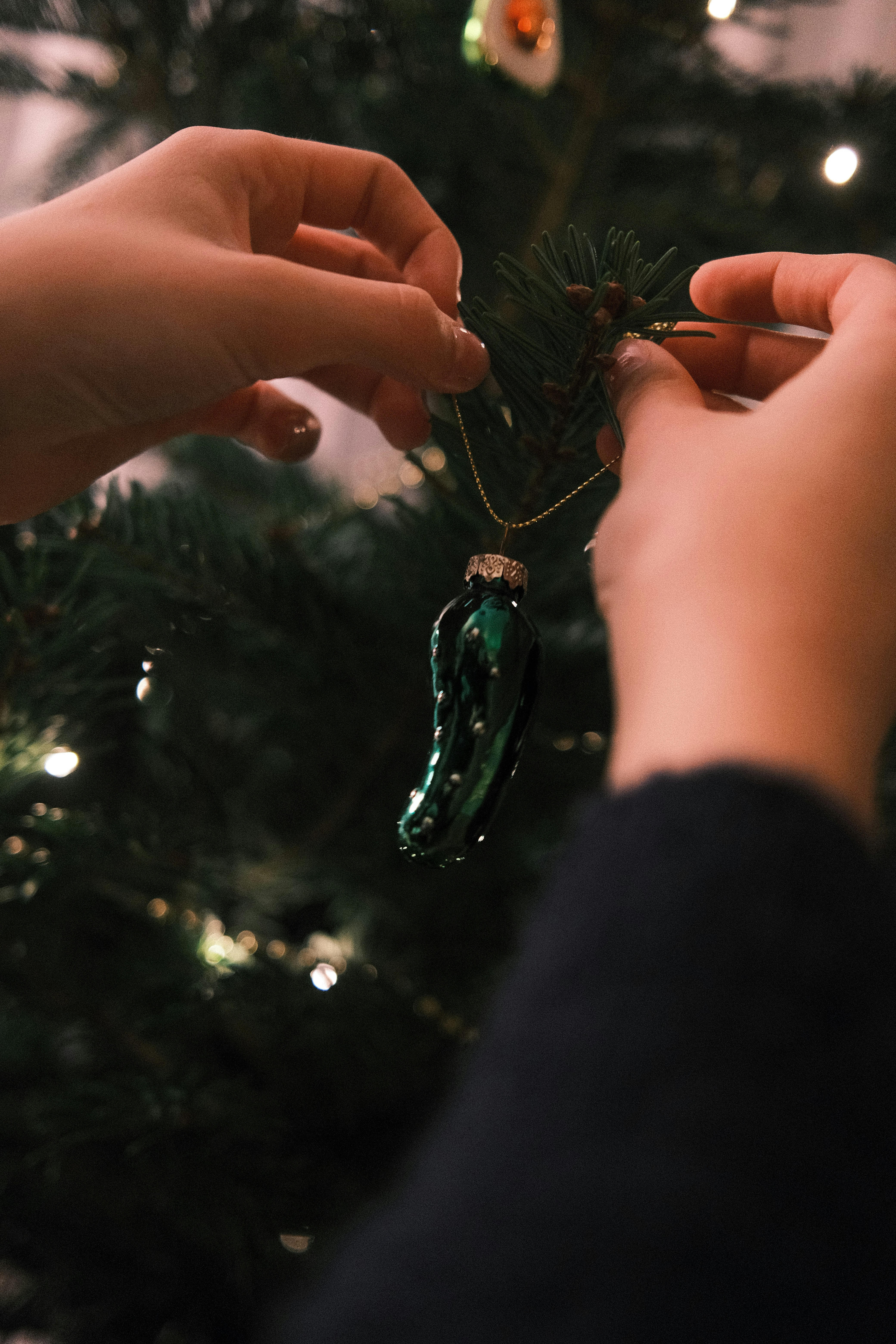 a person holding a green ornament in front of a christmas tree