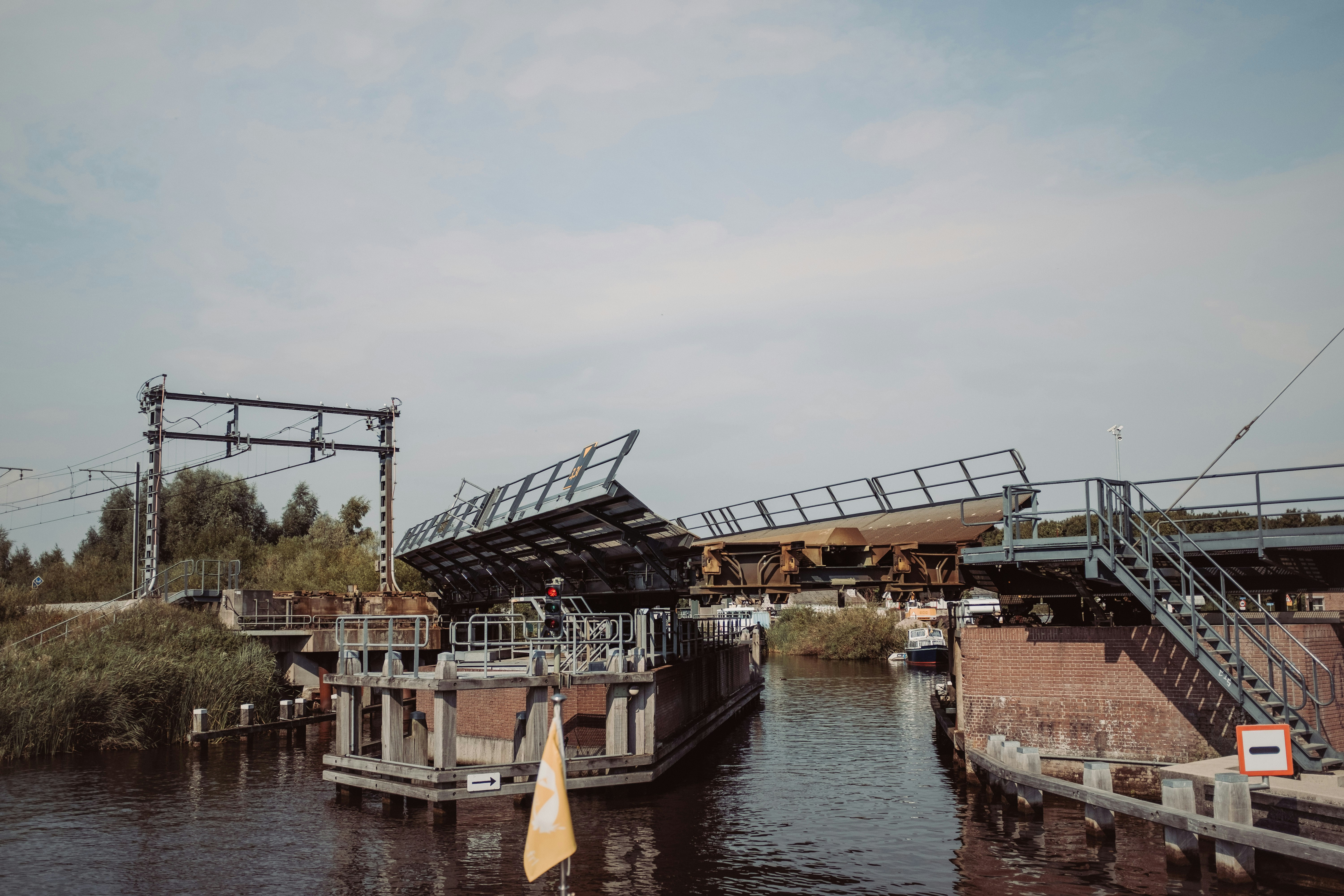 A boat traveling down a river next to a bridge photo – Free Fryslân ...