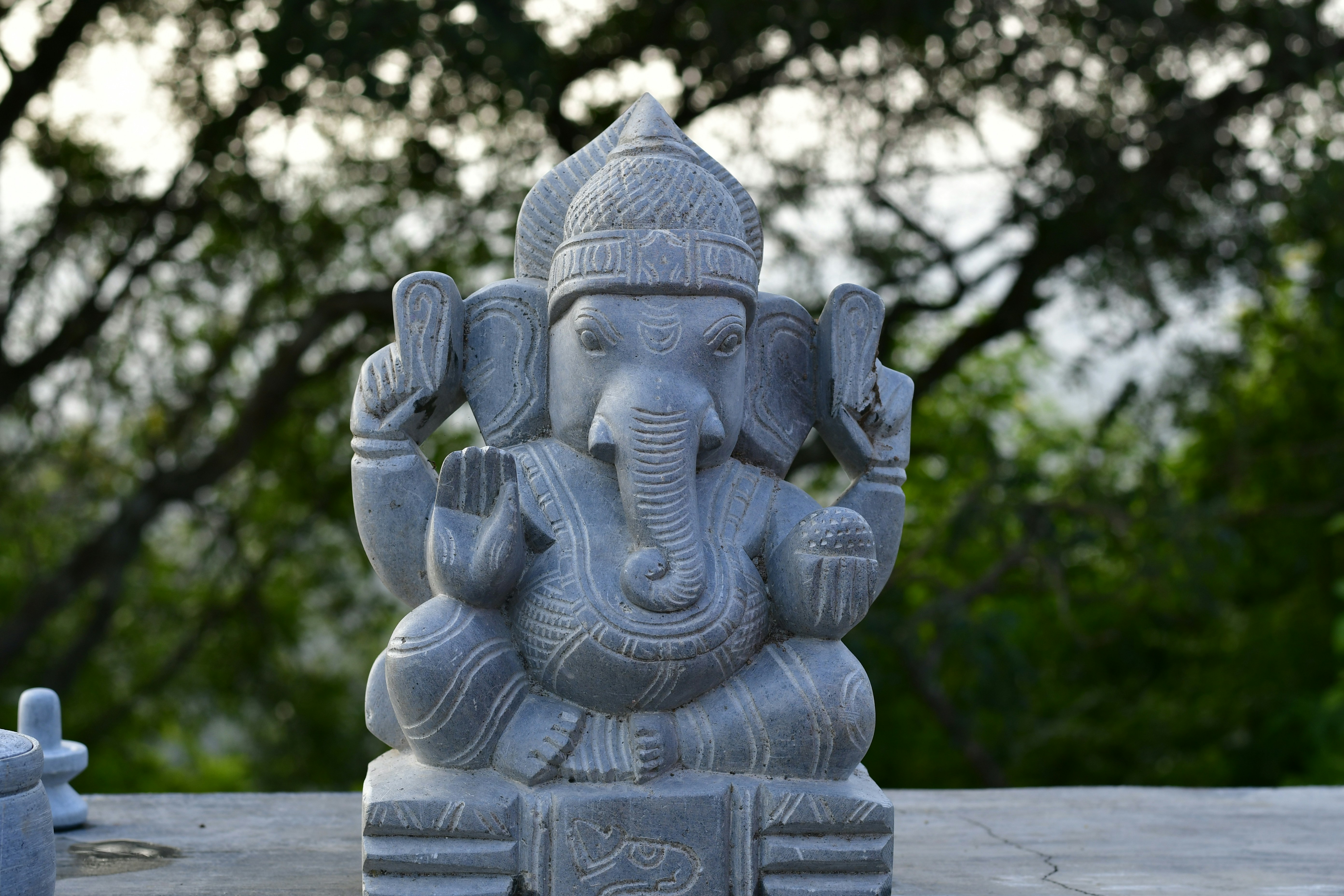 Stone Ganesha: A Focused Portrait in a Leafy Courtyard