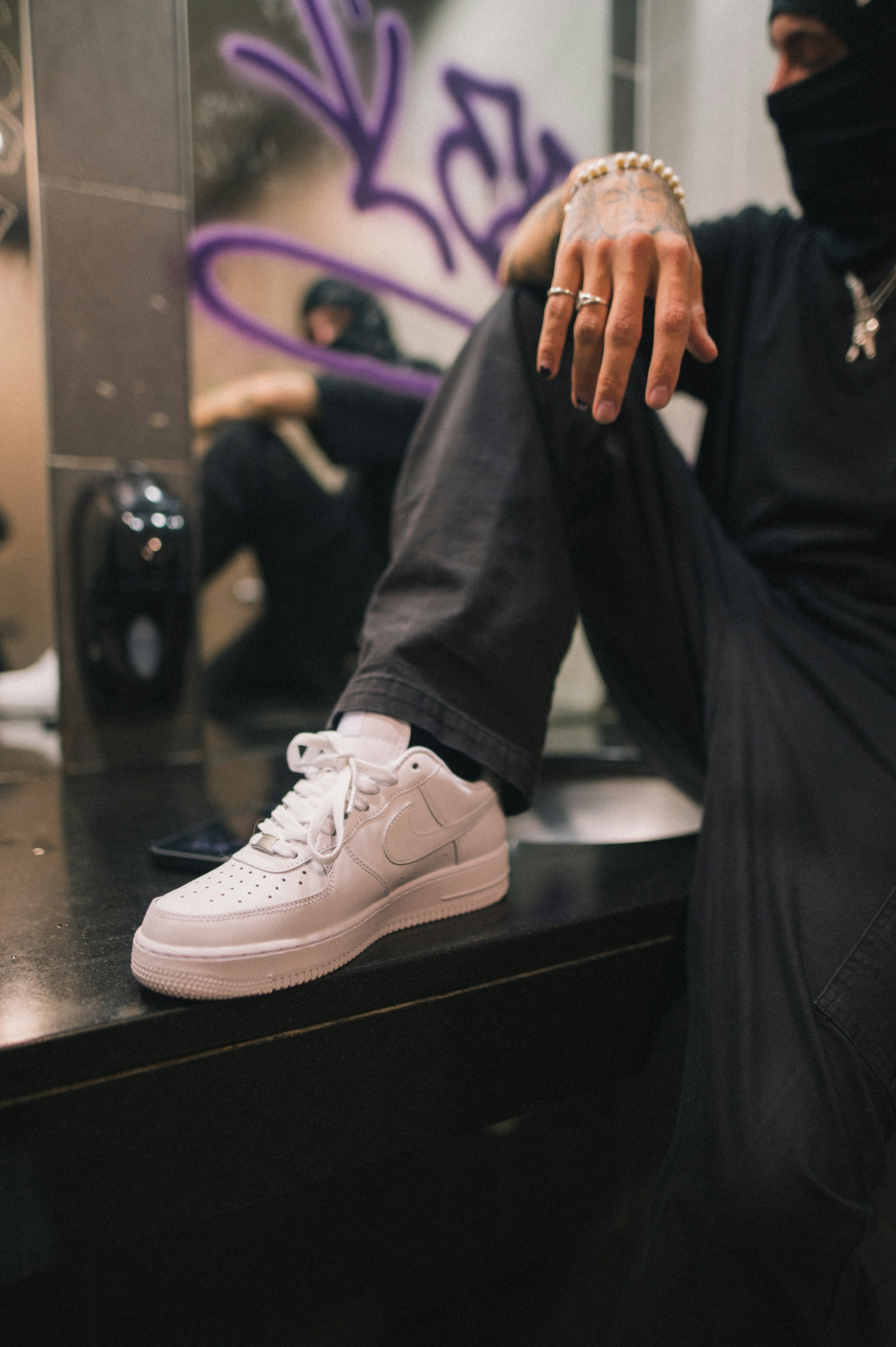 Un homme assis sur un comptoir portant une basket Nike blanche photo ...