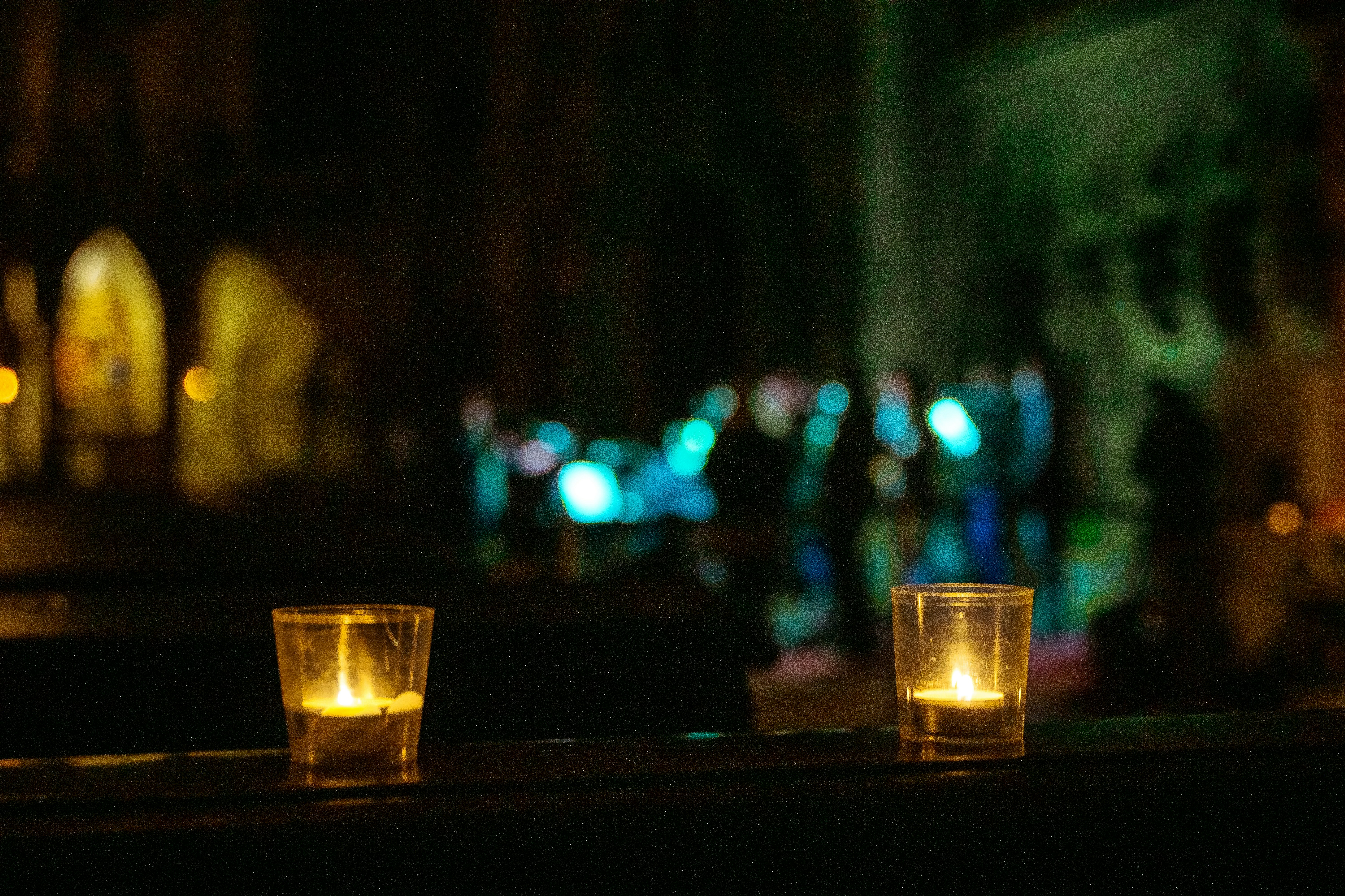 Two Amber Candles Against a Neon-Blurred Night Crowd