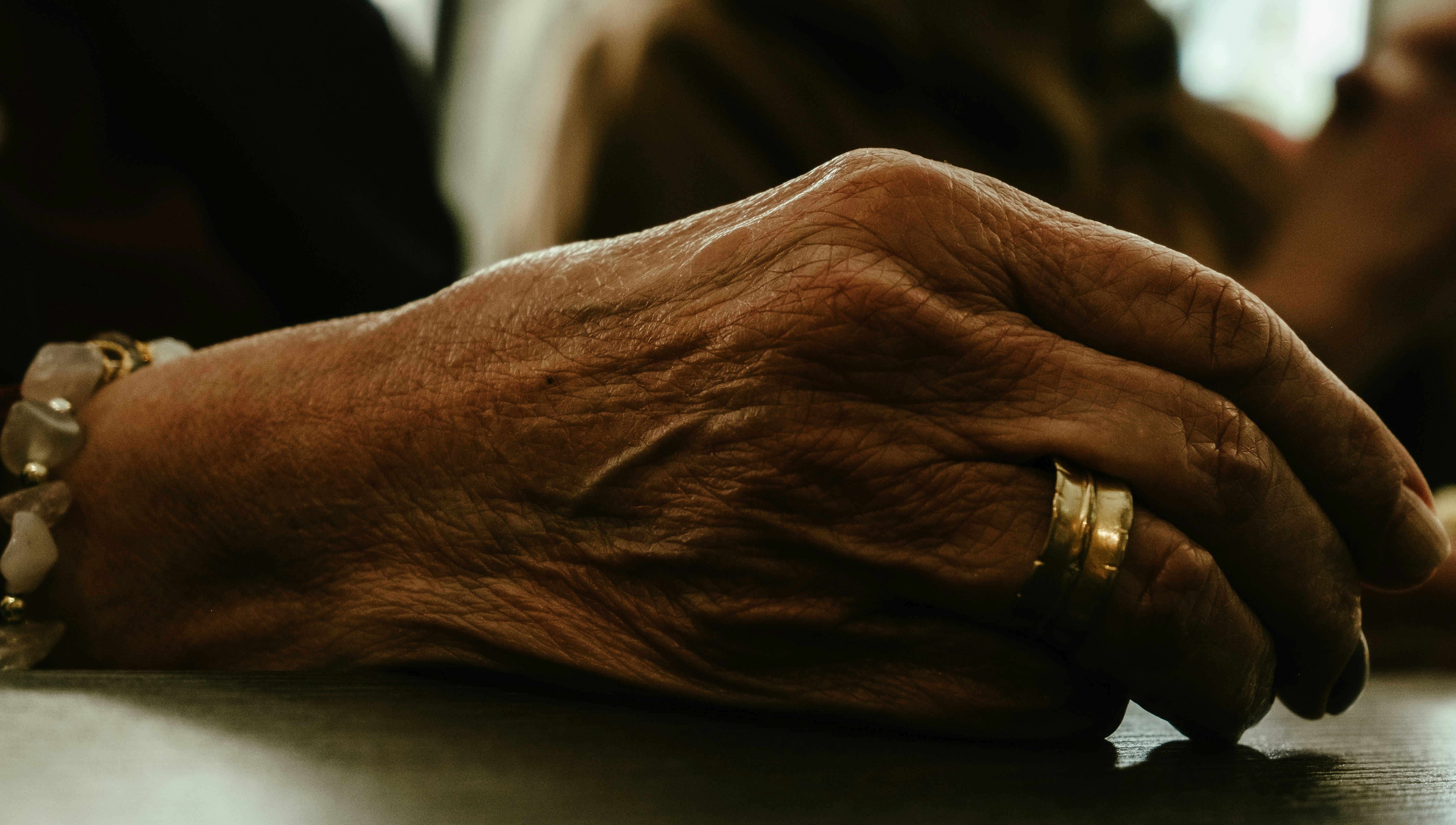 A close up of a person's hands resting on a table photo – Free Hand ...