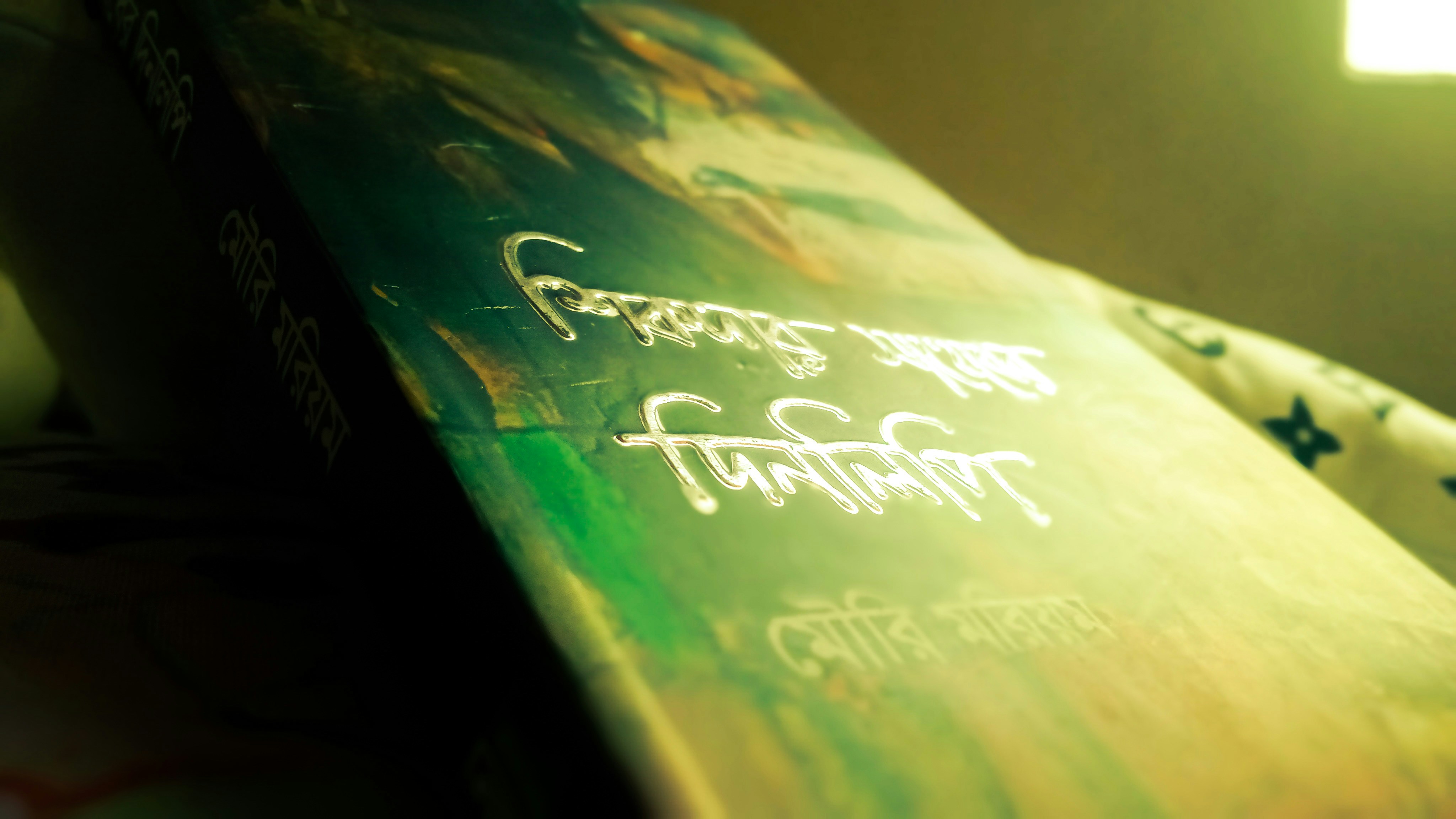 A close-up of a book with an artistic cover, illuminated by soft natural light, resting on a patterned surface.