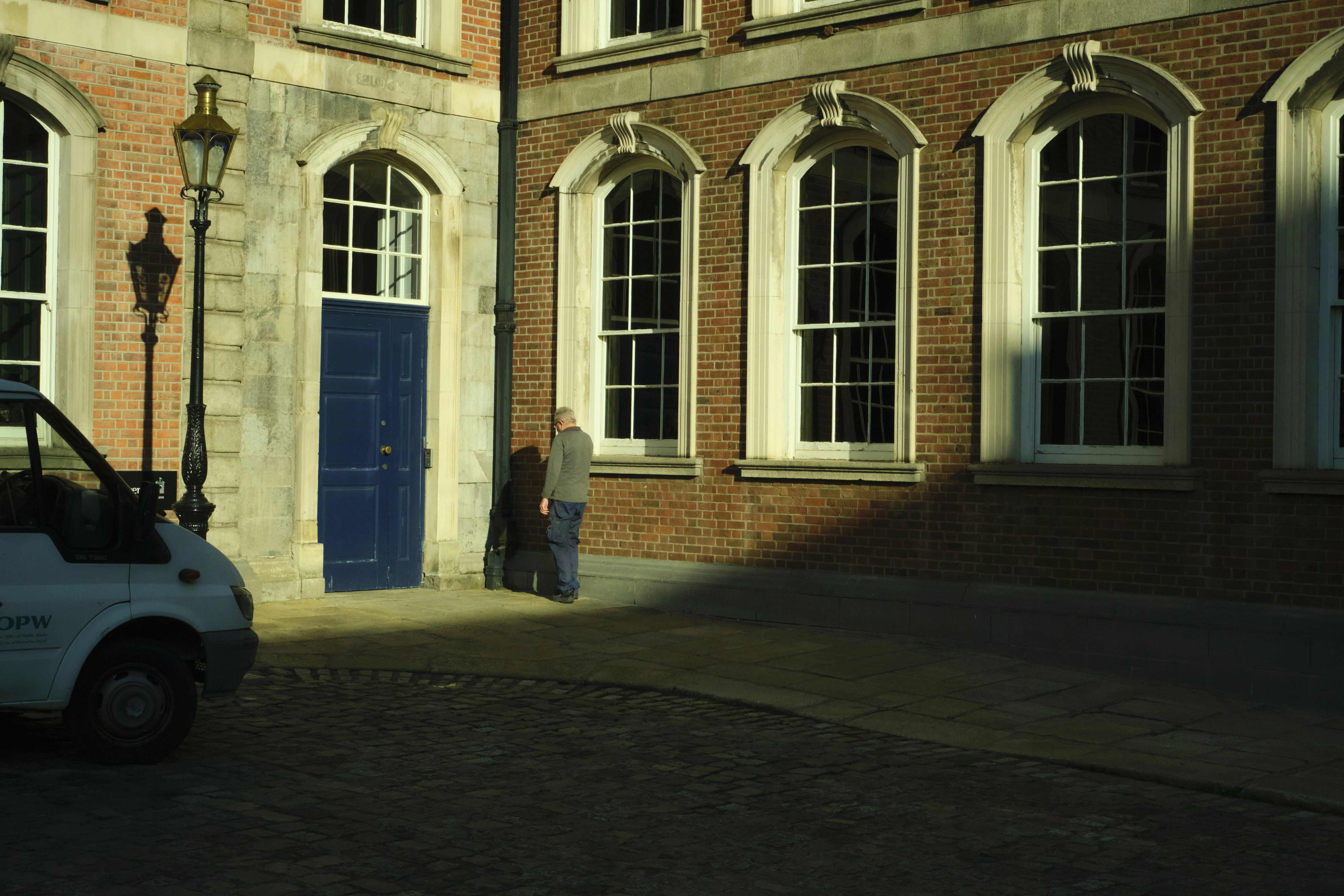 A white van parked in front of a tall brick building photo – Free ...
