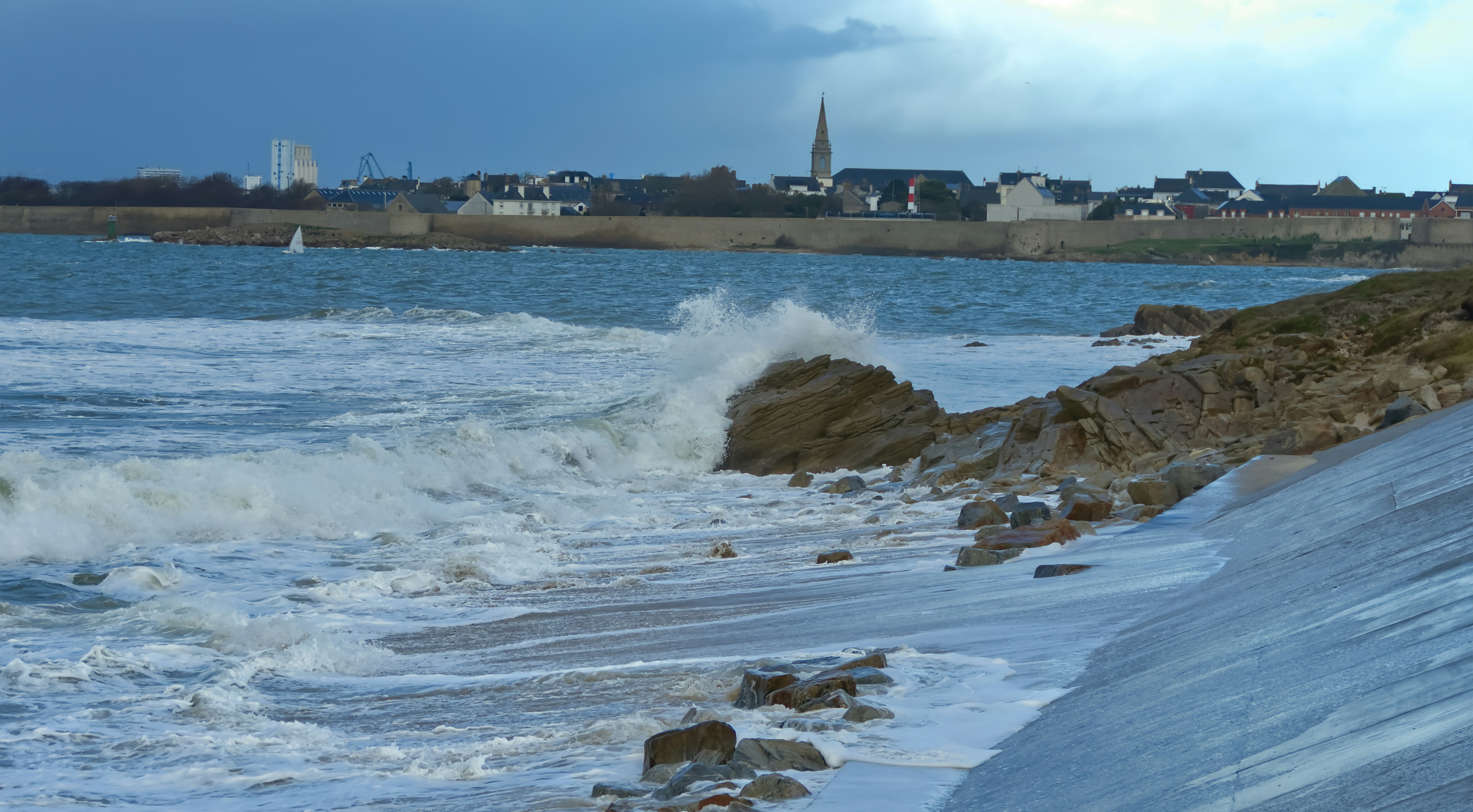 Waves at the Edge: A Rugged Shore Leading the Eye to a Quiet Coastal Town