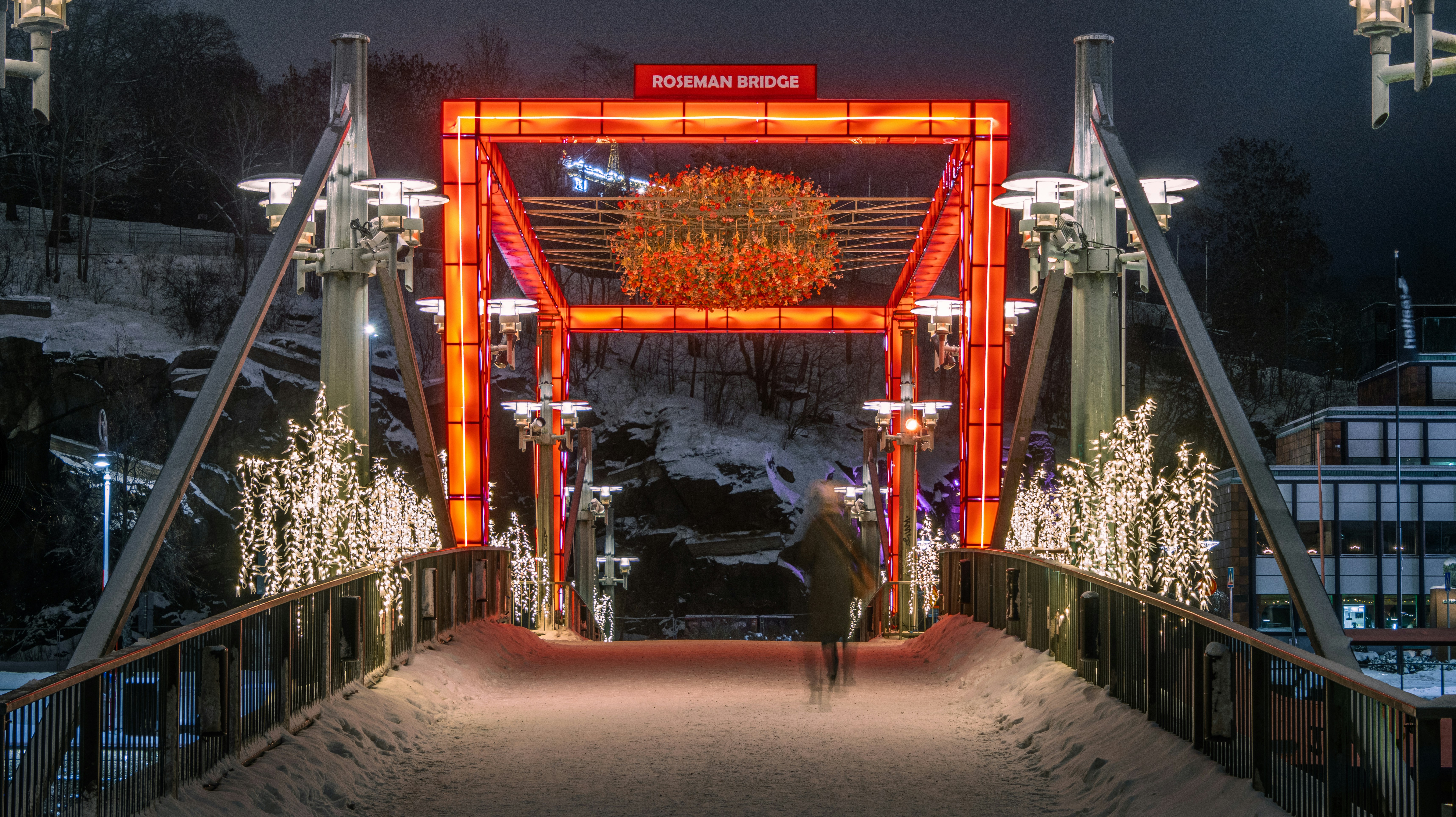 Illuminated Archway Over Snow-Covered River Walk