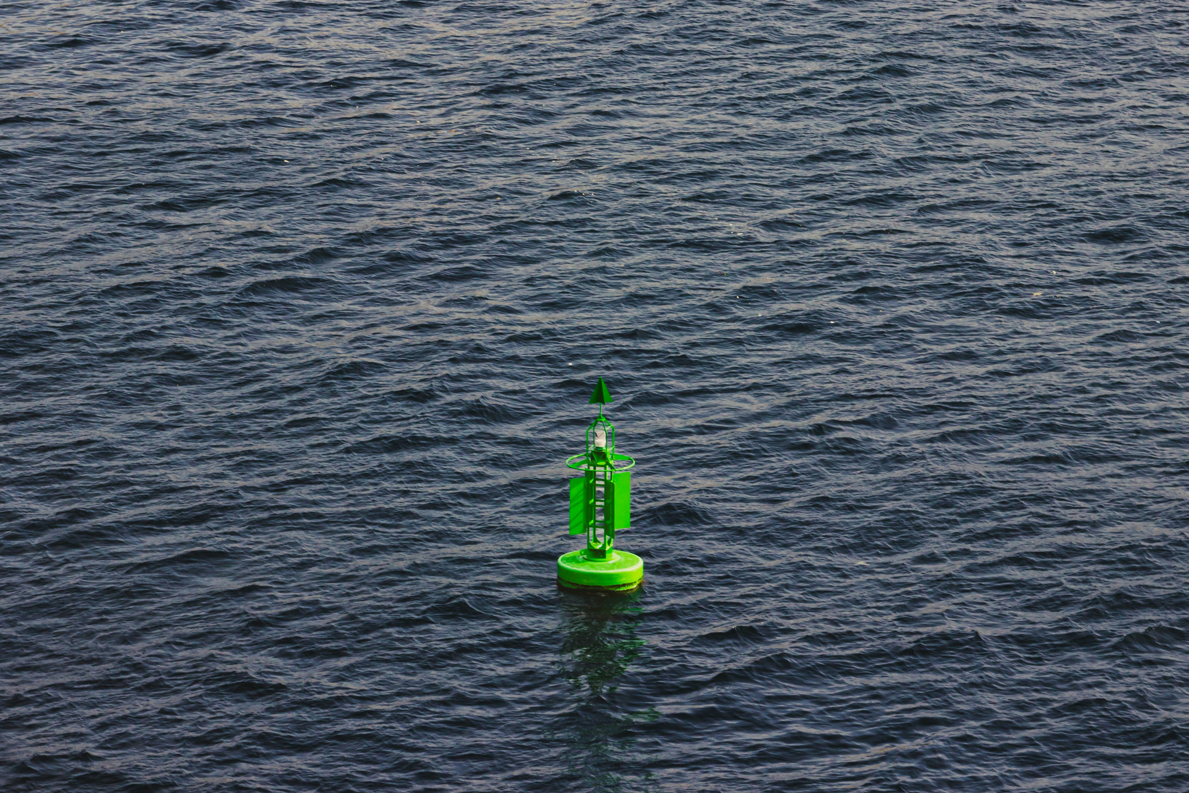 A green buoy floating in the middle of a body of water photo – Free ...