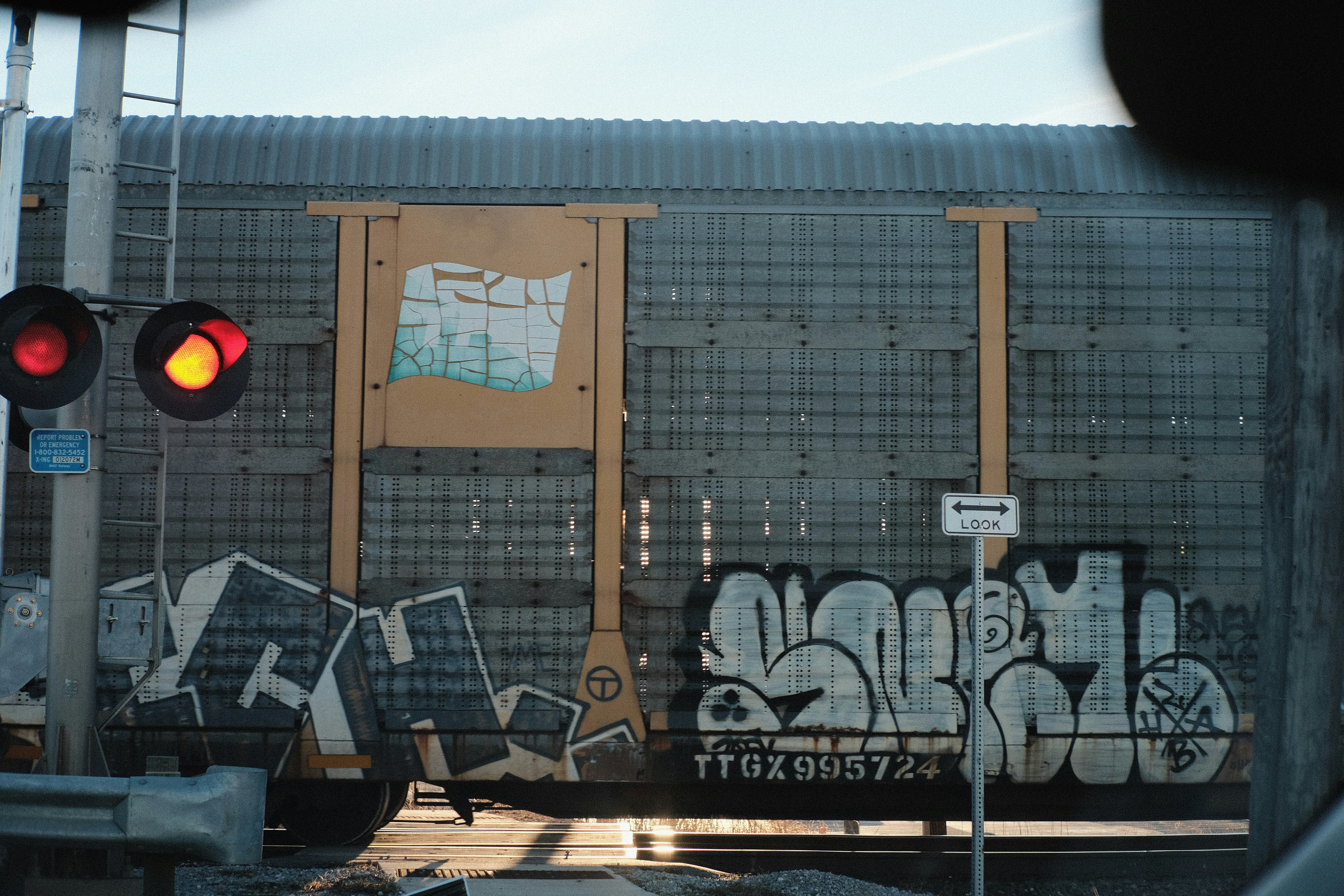 Graffiti-covered train car adorned with a painted window frame, juxtaposed against a backdrop of traffic signals and signage.