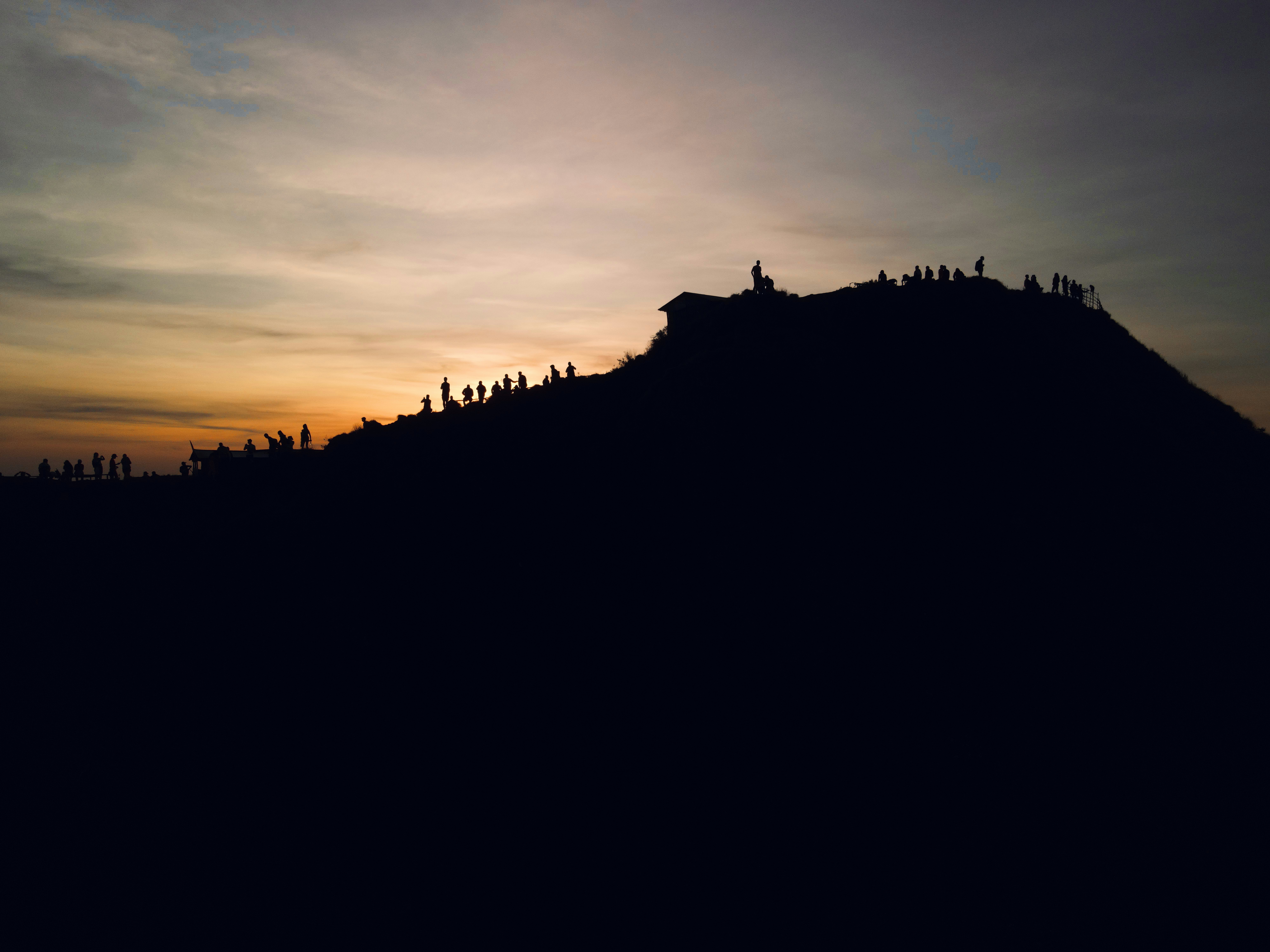 The sun is setting over a hill with trees on it photo – Free Batur ...