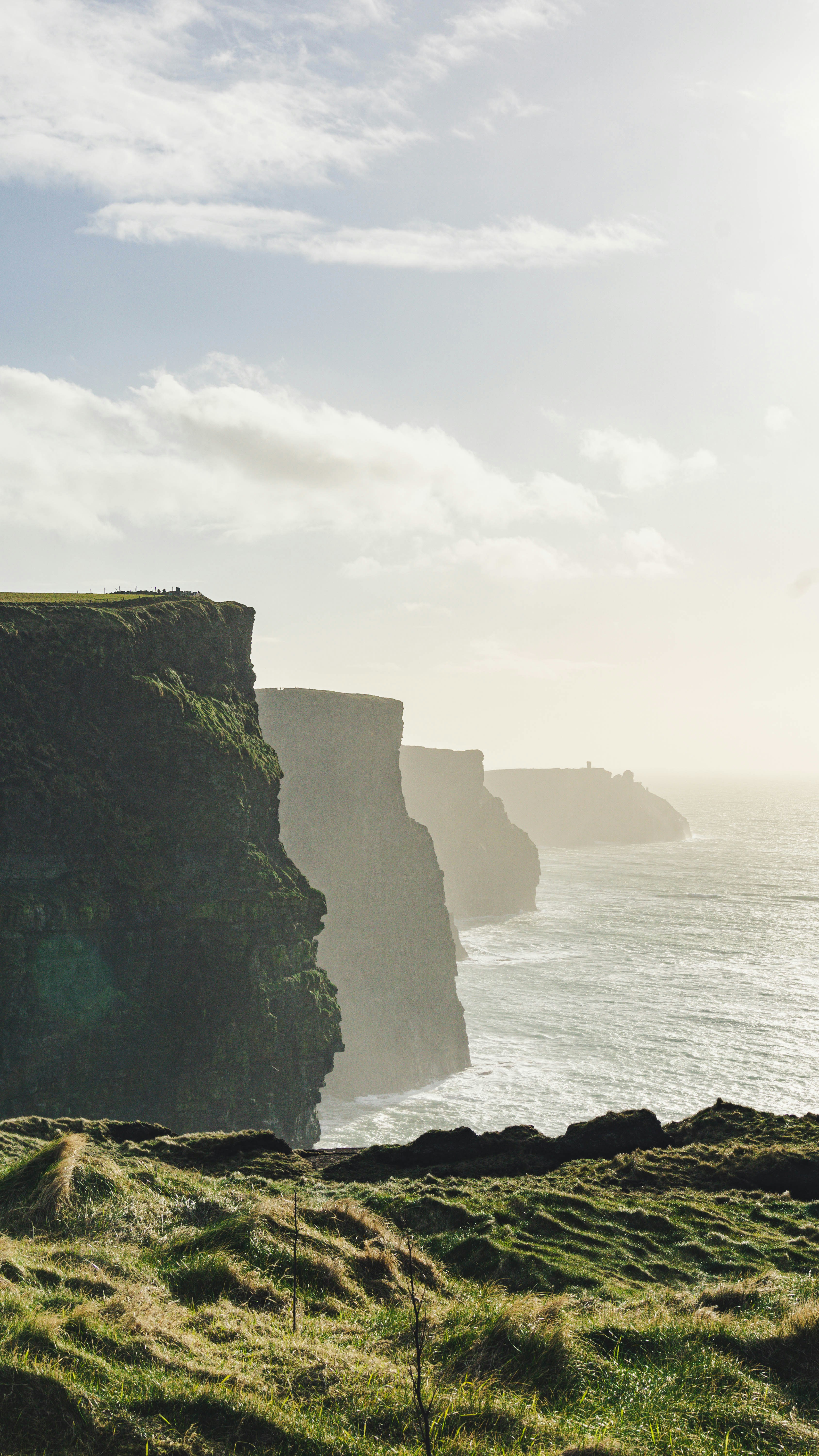 A grassy field next to a cliff overlooking the ocean photo – Free ...