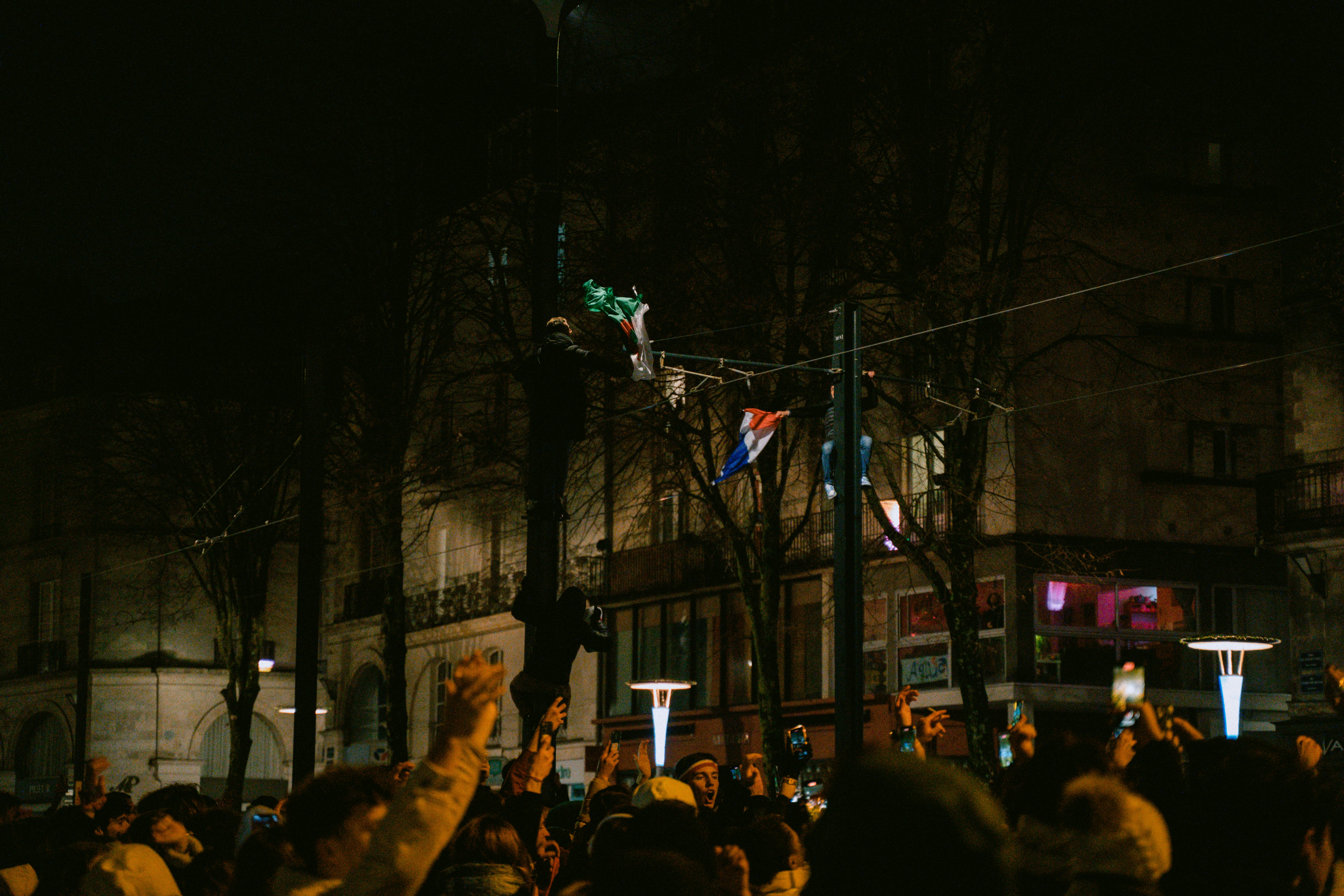 a crowd of people standing on a street at night
