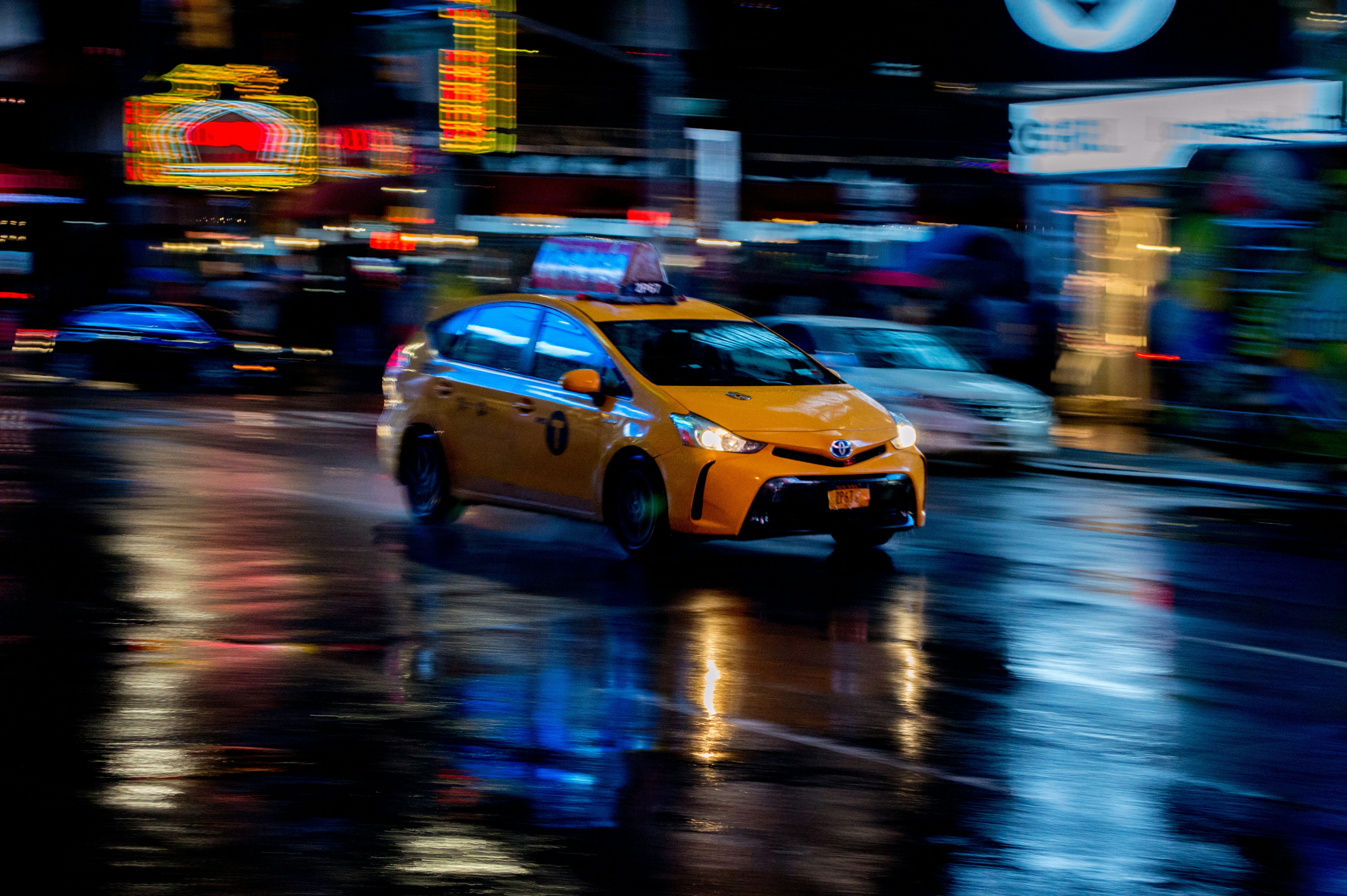 A yellow taxi cab driving down a rain soaked street photo – Free Times ...