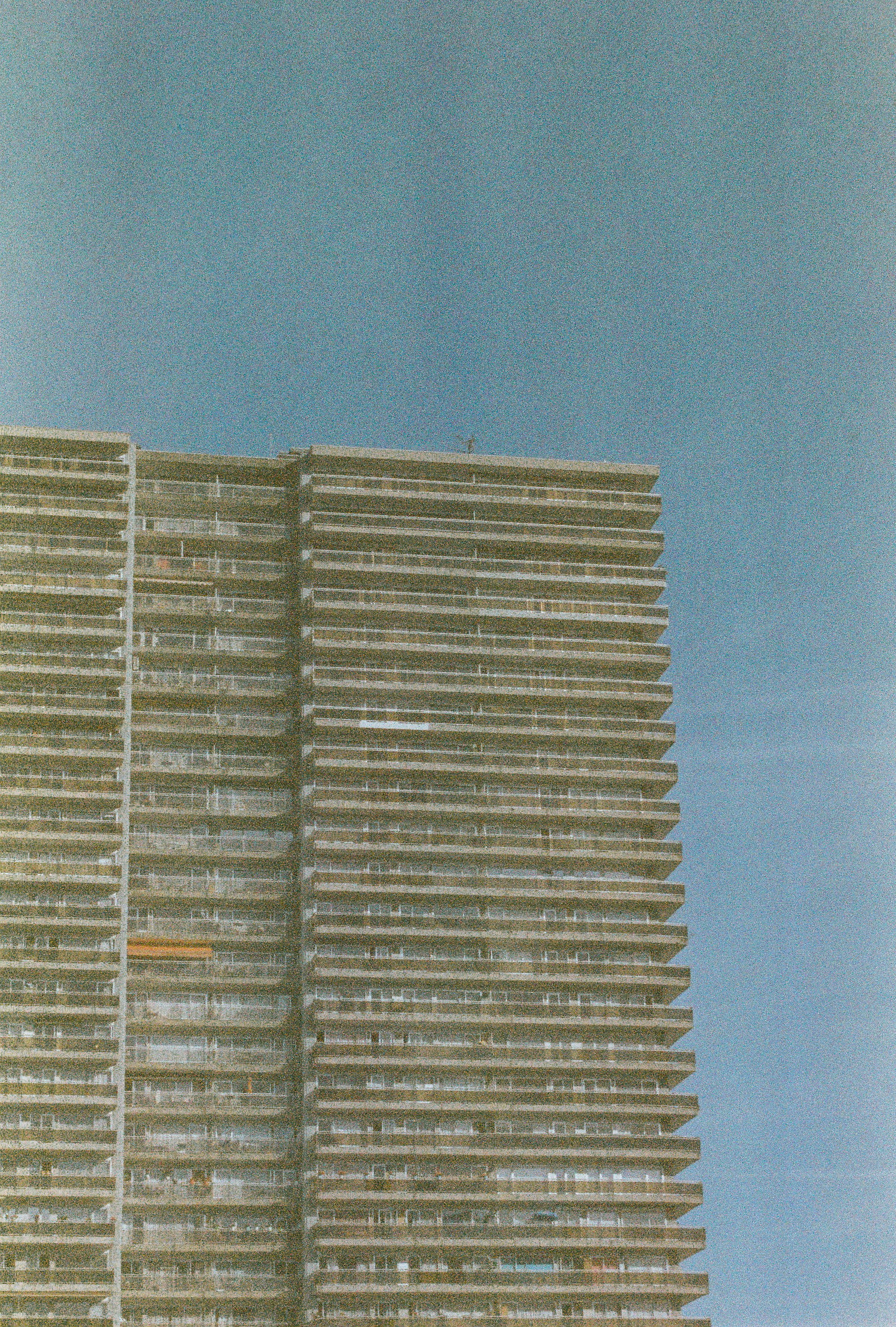 A high-rise building with a repetitive facade against a clear blue sky, showcasing modern architectural design.