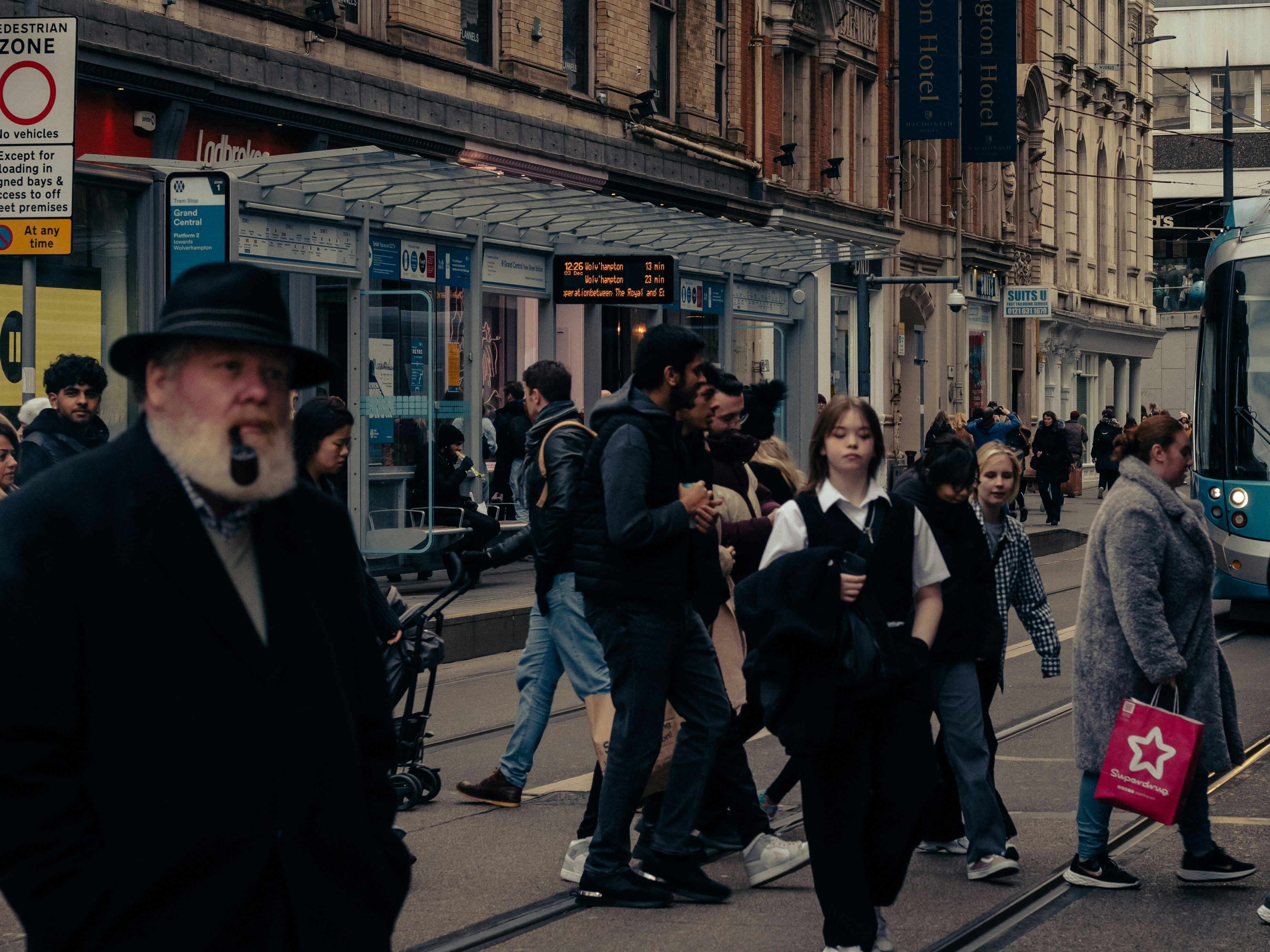 People crossing a street at Birmingham city, England | a group of people walking down a street next to a bus
