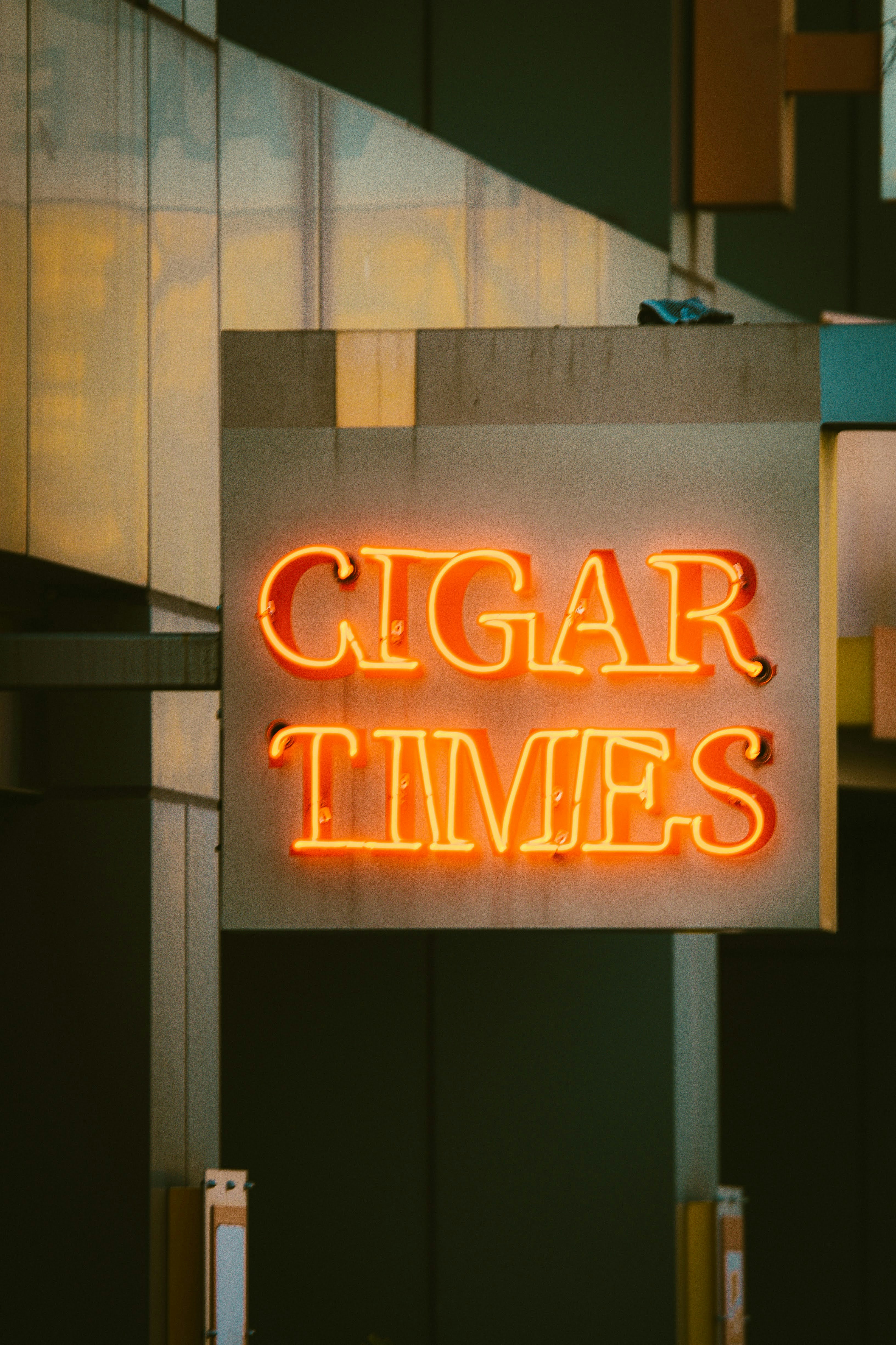 CIGAR TIMES Neon: Warm Orange Glow on a Geometric Facade