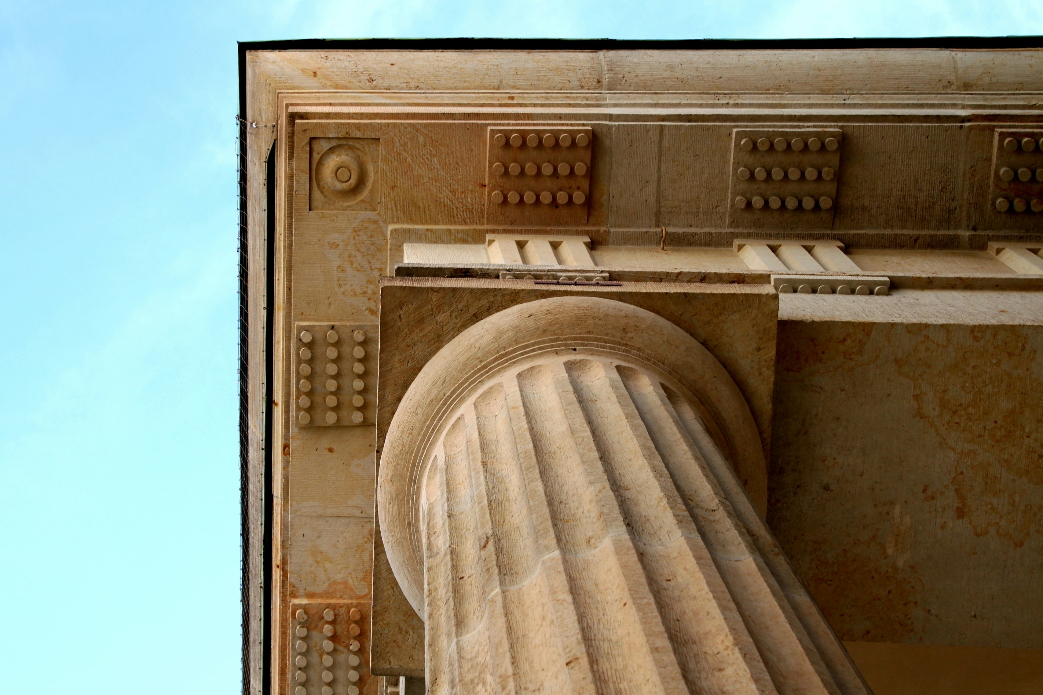 Close-up view of a classical column and ornate ceiling details, showcasing intricate craftsmanship and architectural grandeur.