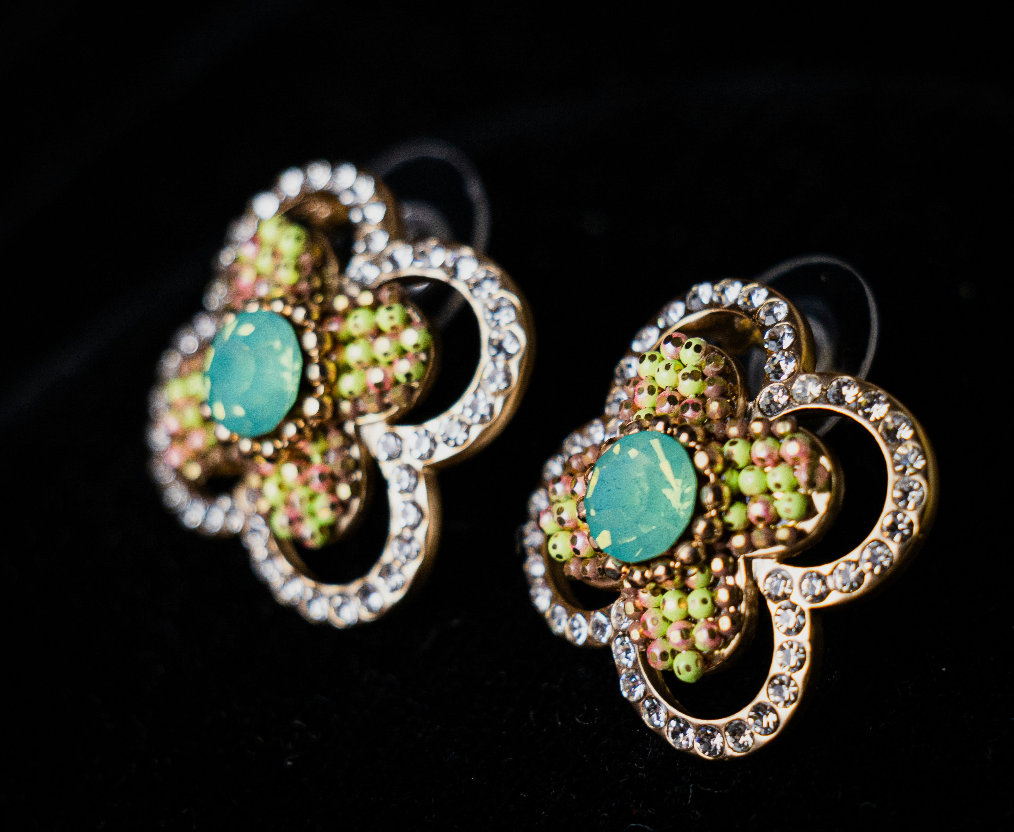 a pair of green and white earrings on a black surface