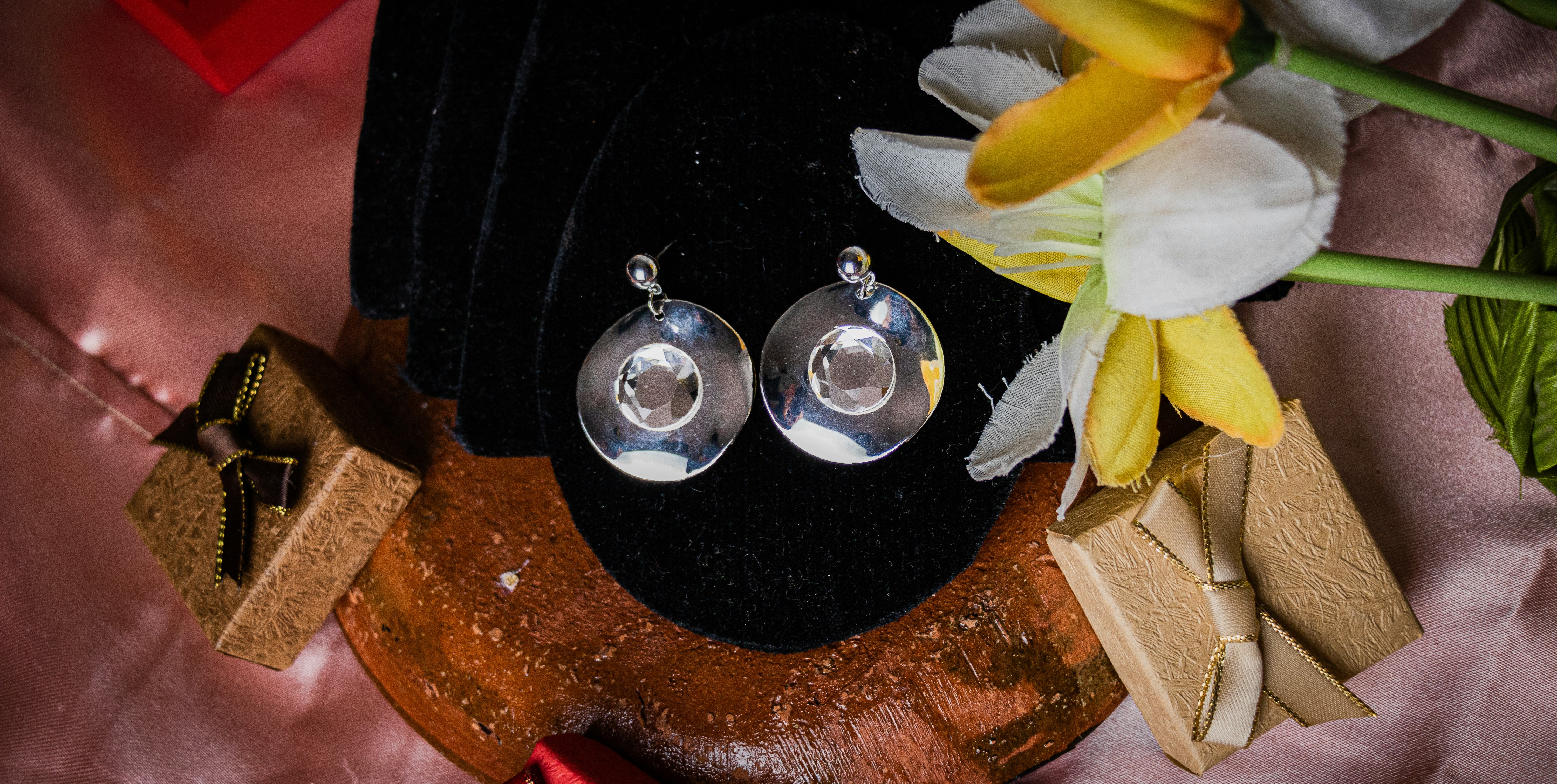 Twin Silver Disc Earrings Rest on Velvet, Framed by Gifts and Daffodils