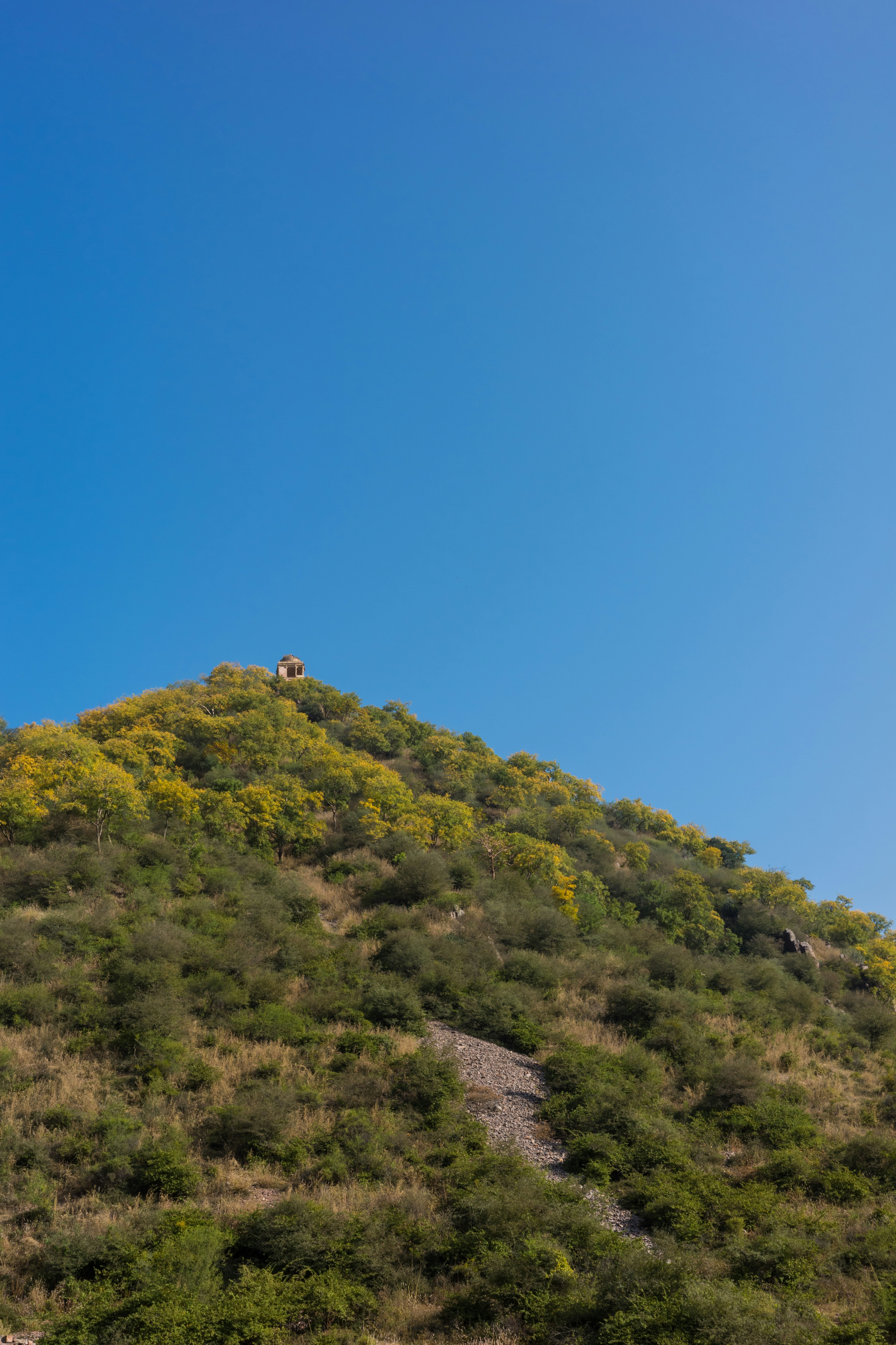 Hilltop Shrine Above Emerald Slopes under a Vast Blue Sky